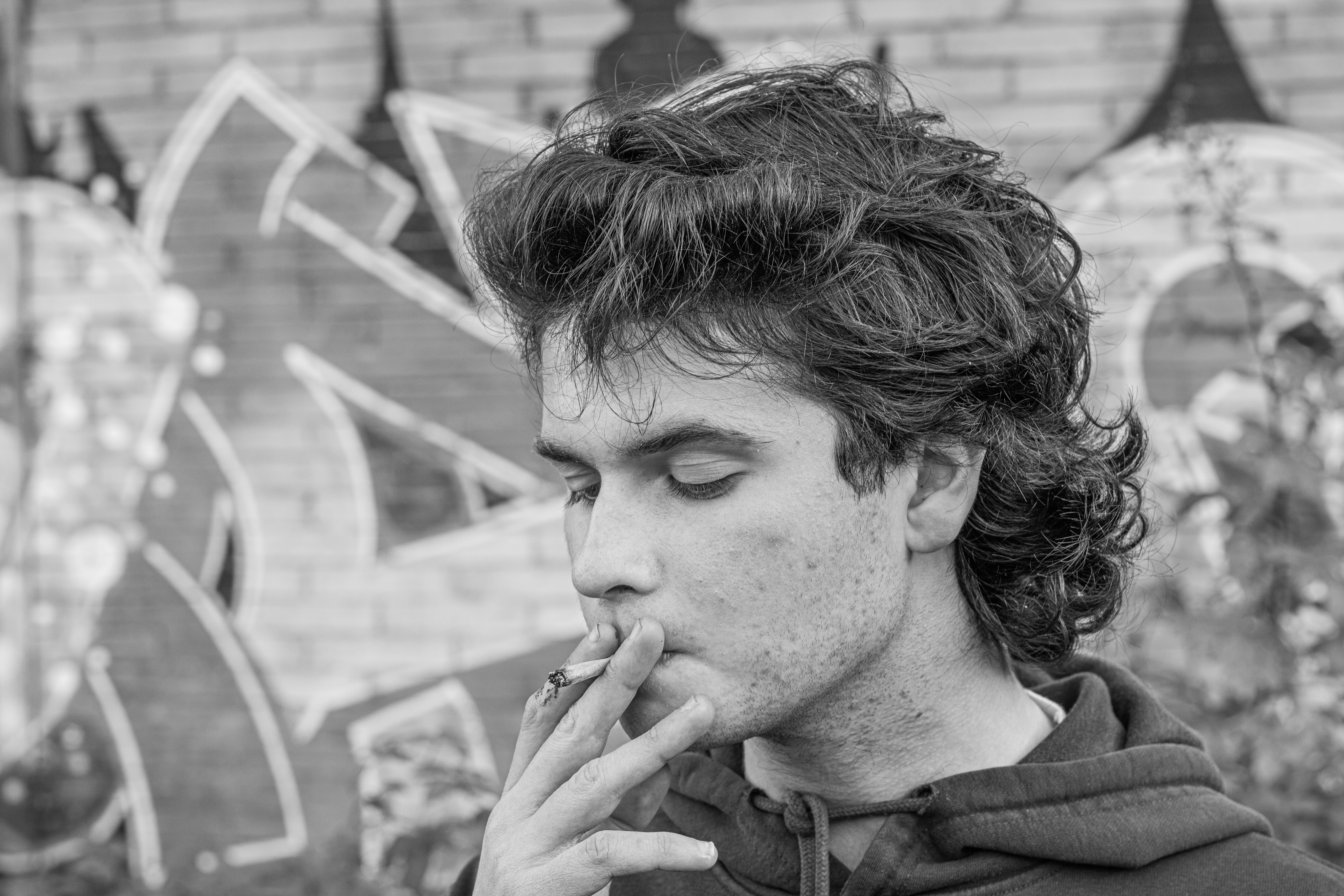 A man smoking a cigarette in front of a graffiti wall photo – Free ...
