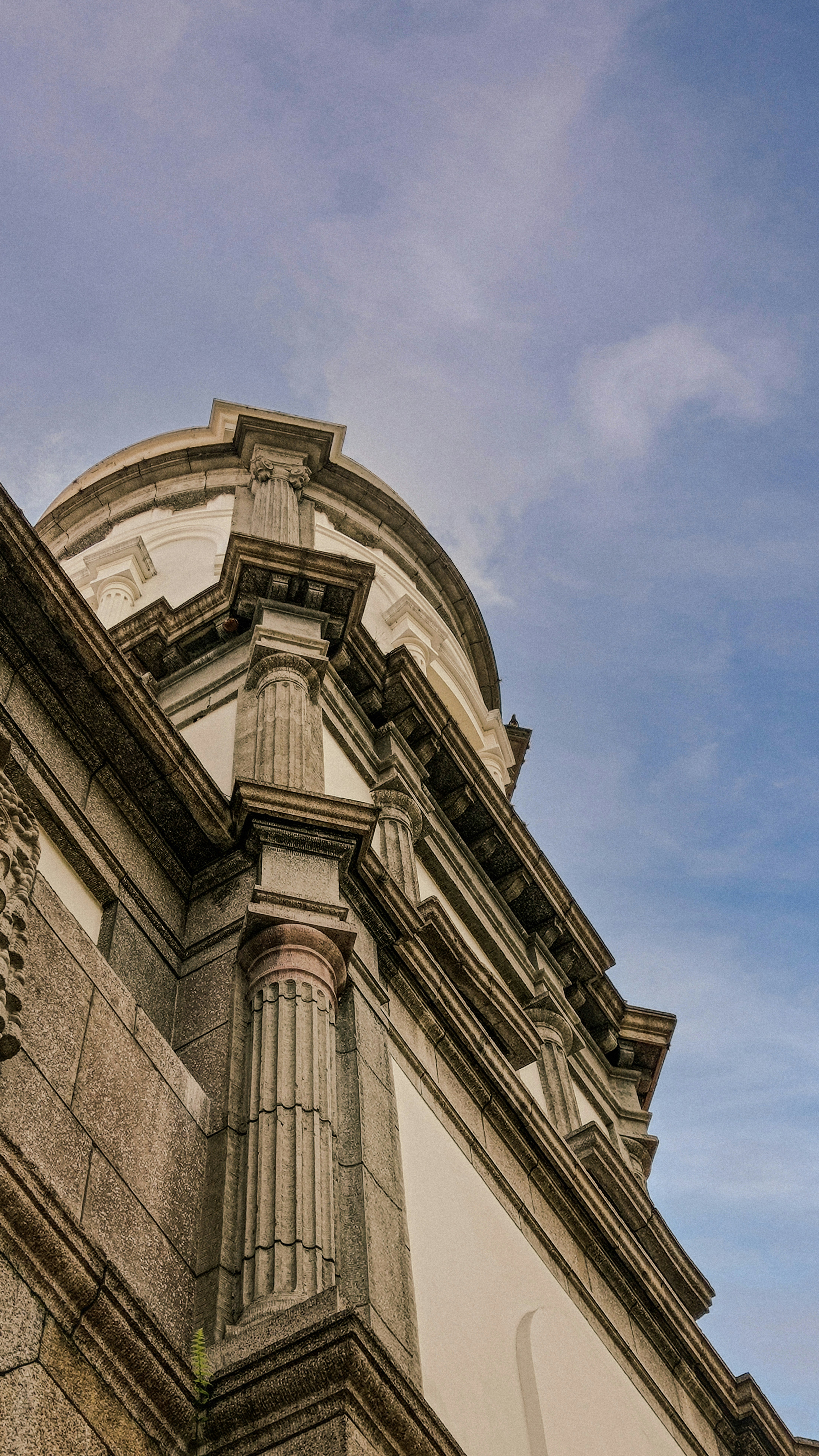 Detailed view of a historic building's ornate columns and dome against a clear sky.