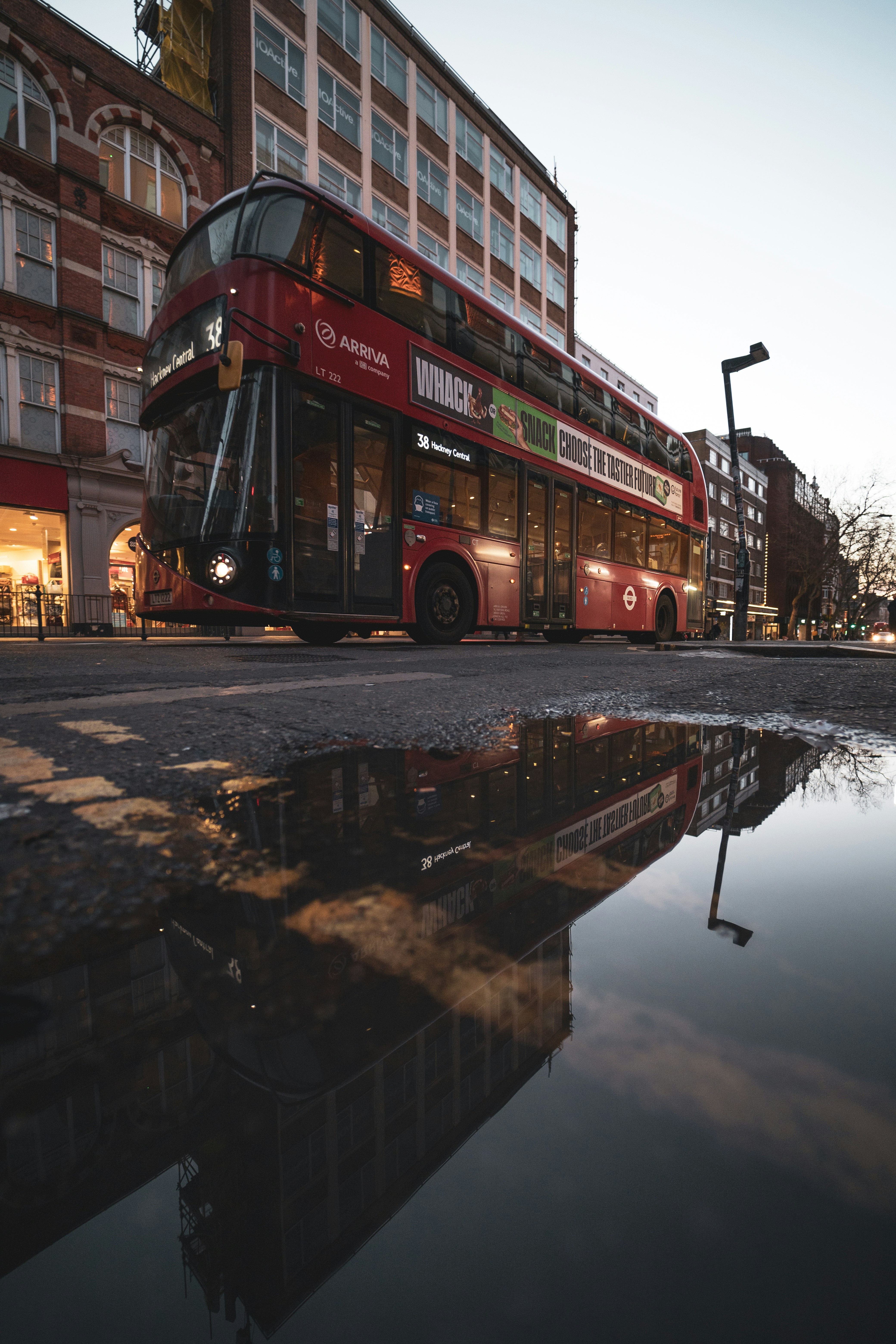 London Bus on Wet Street: Reflections Under Evening Sky