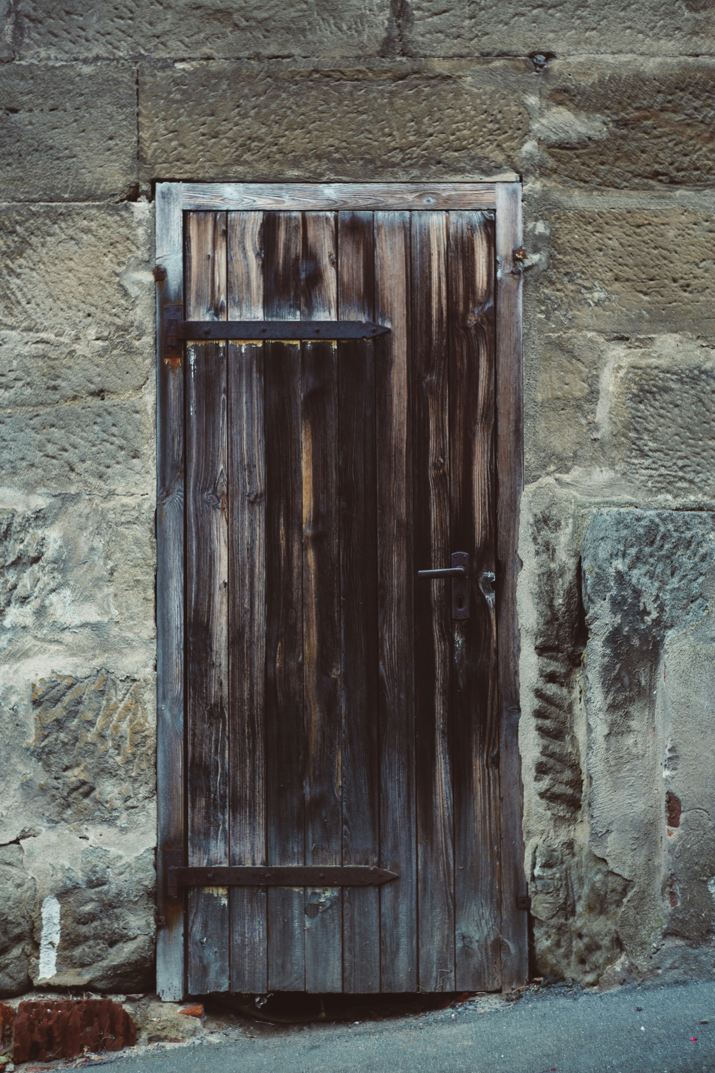 Weathered wooden door set against a textured stone wall, hinting at stories untold.