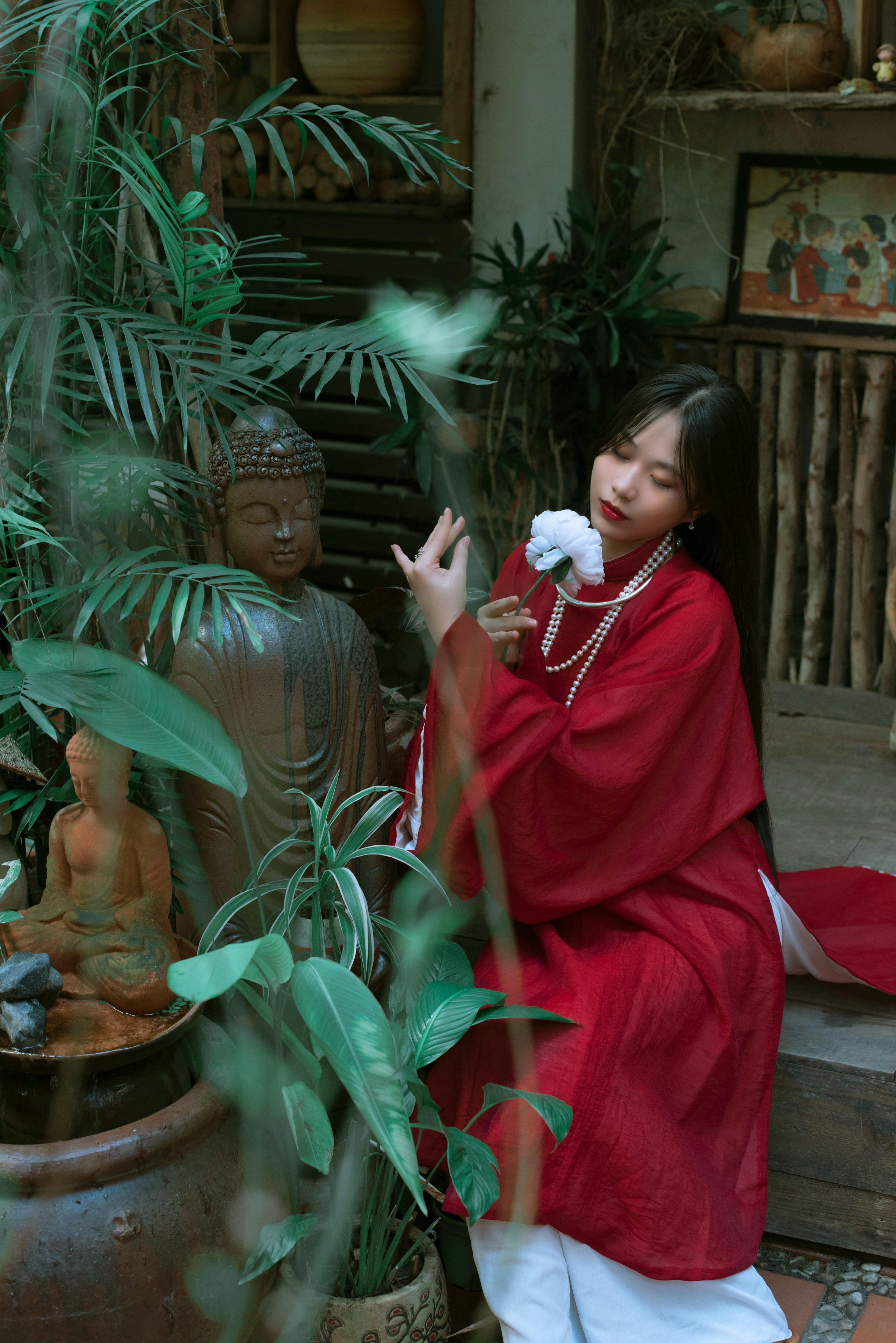 Una mujer con un vestido rojo sentada junto a una estatua de Buda foto ...