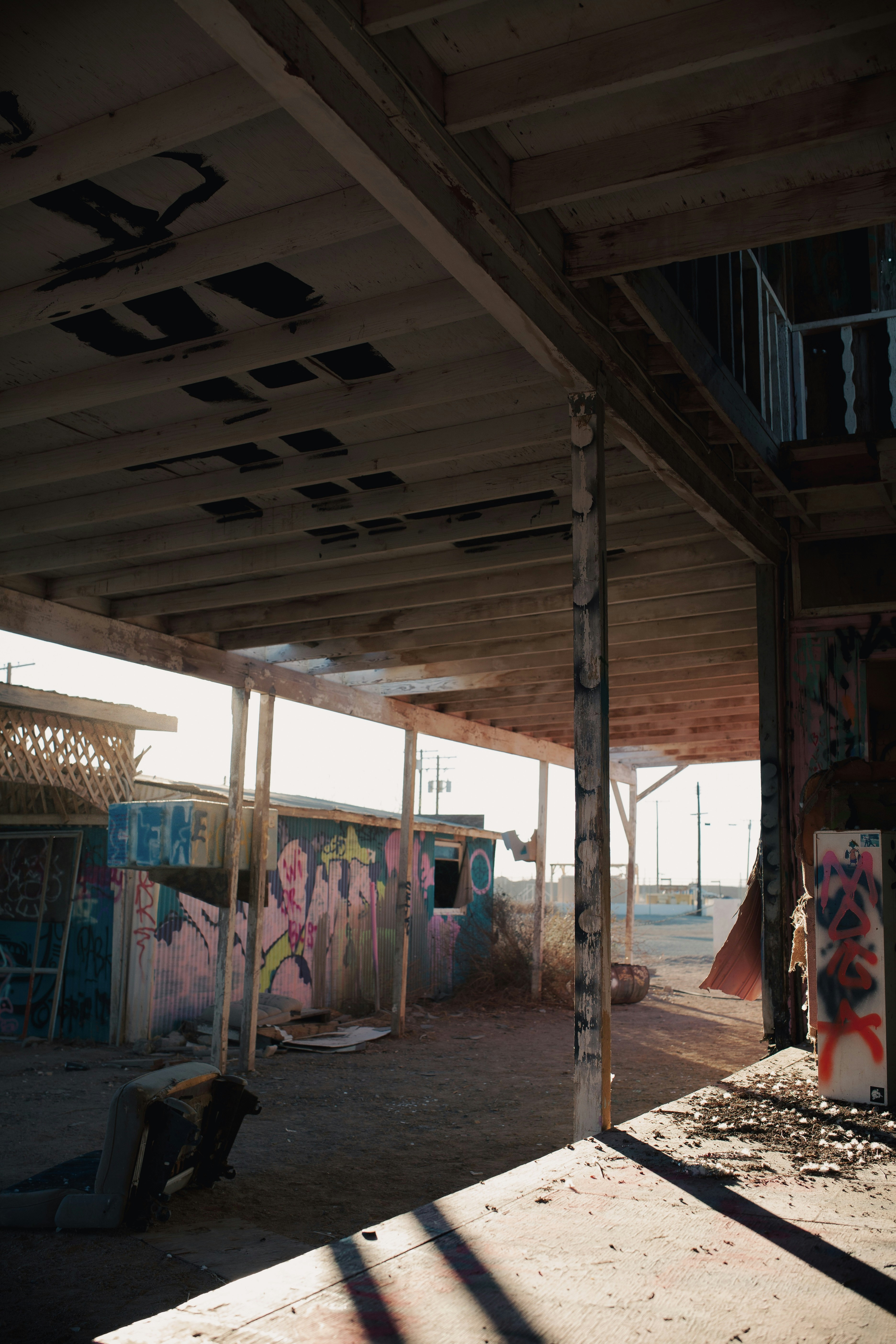 Sunlit Alley Beneath a Graffiti-Streaked Structure