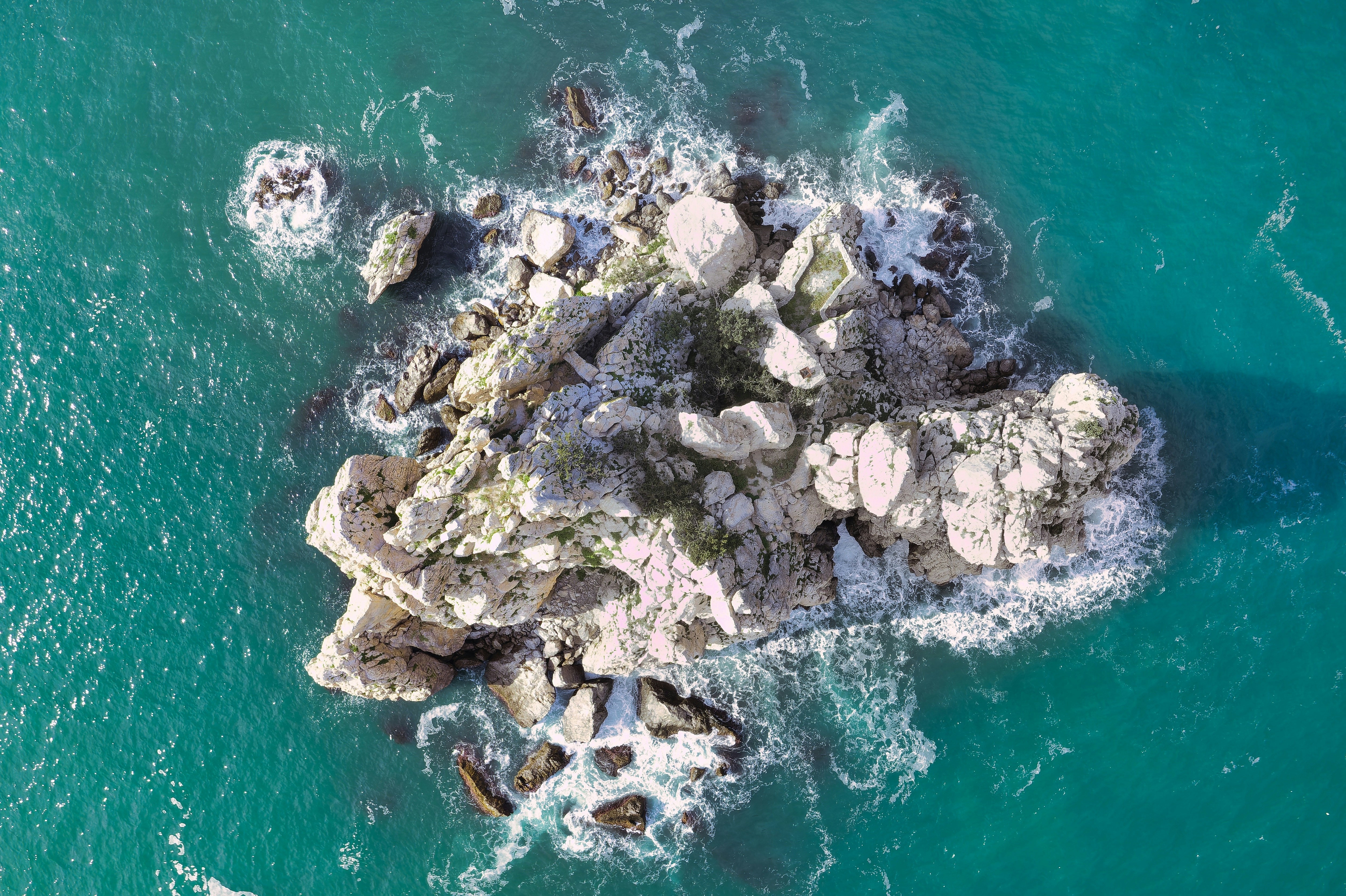 Isolated Sea-Ring: Aerial View of a Rocky Outcrop Embraced by Turquoise Waters