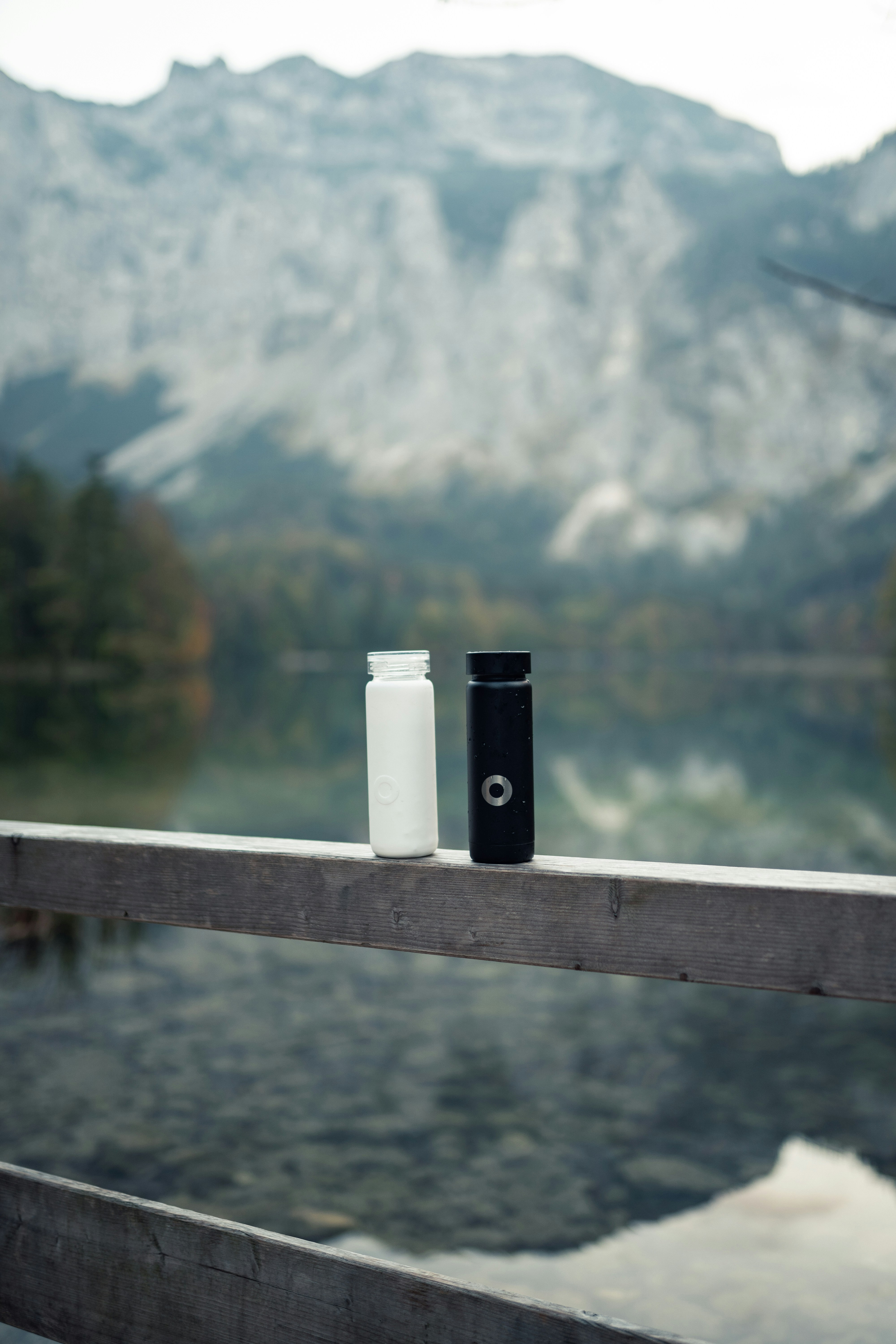 Two Vials on a Weathered Rail Over a Misty Alpine Lake