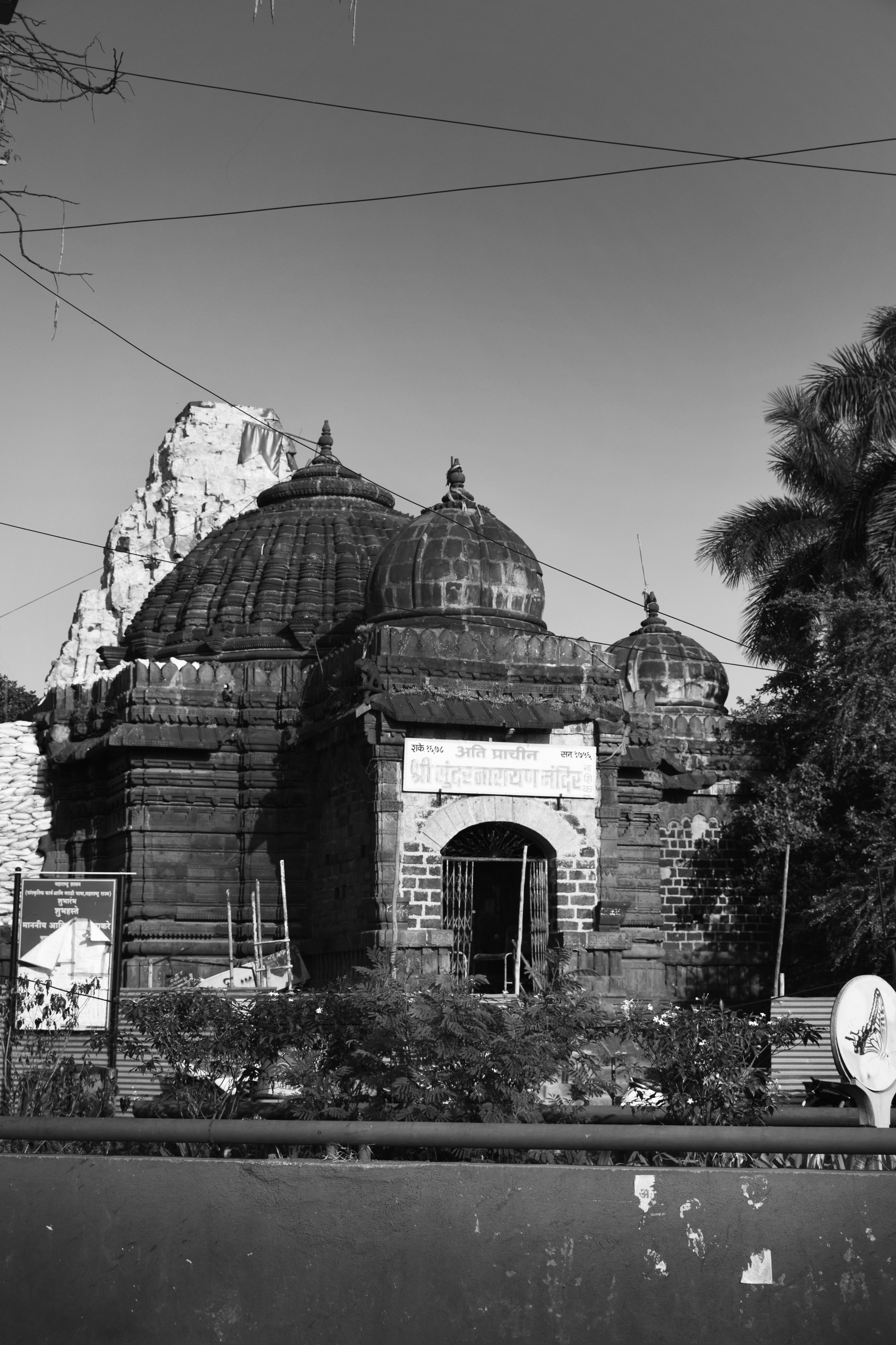 Ancient dome-temple under a clear sky, framed by tropical greenery