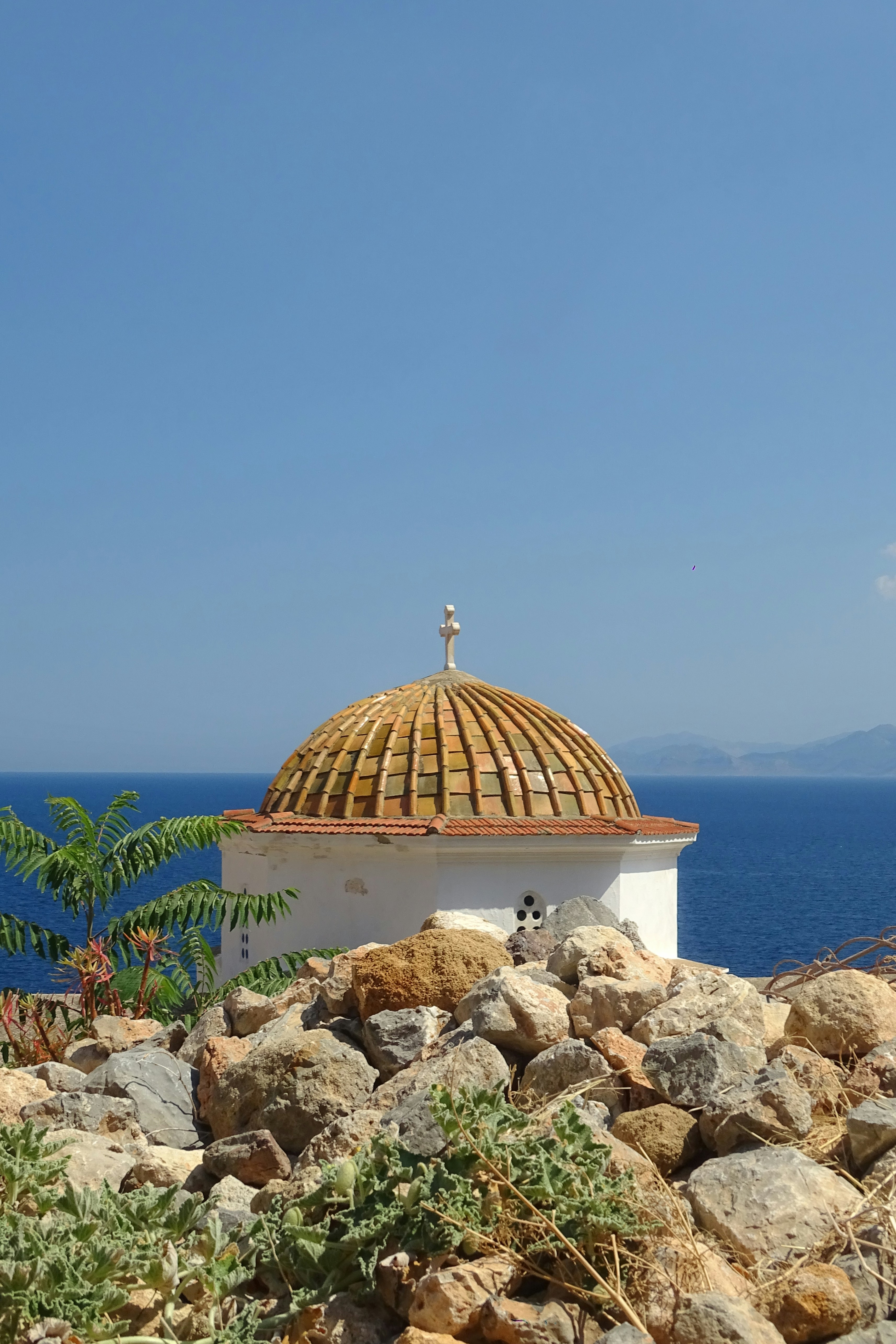 Terracotta Dome by the Sea: A Quiet Chapel Framed by Rugged Foreground