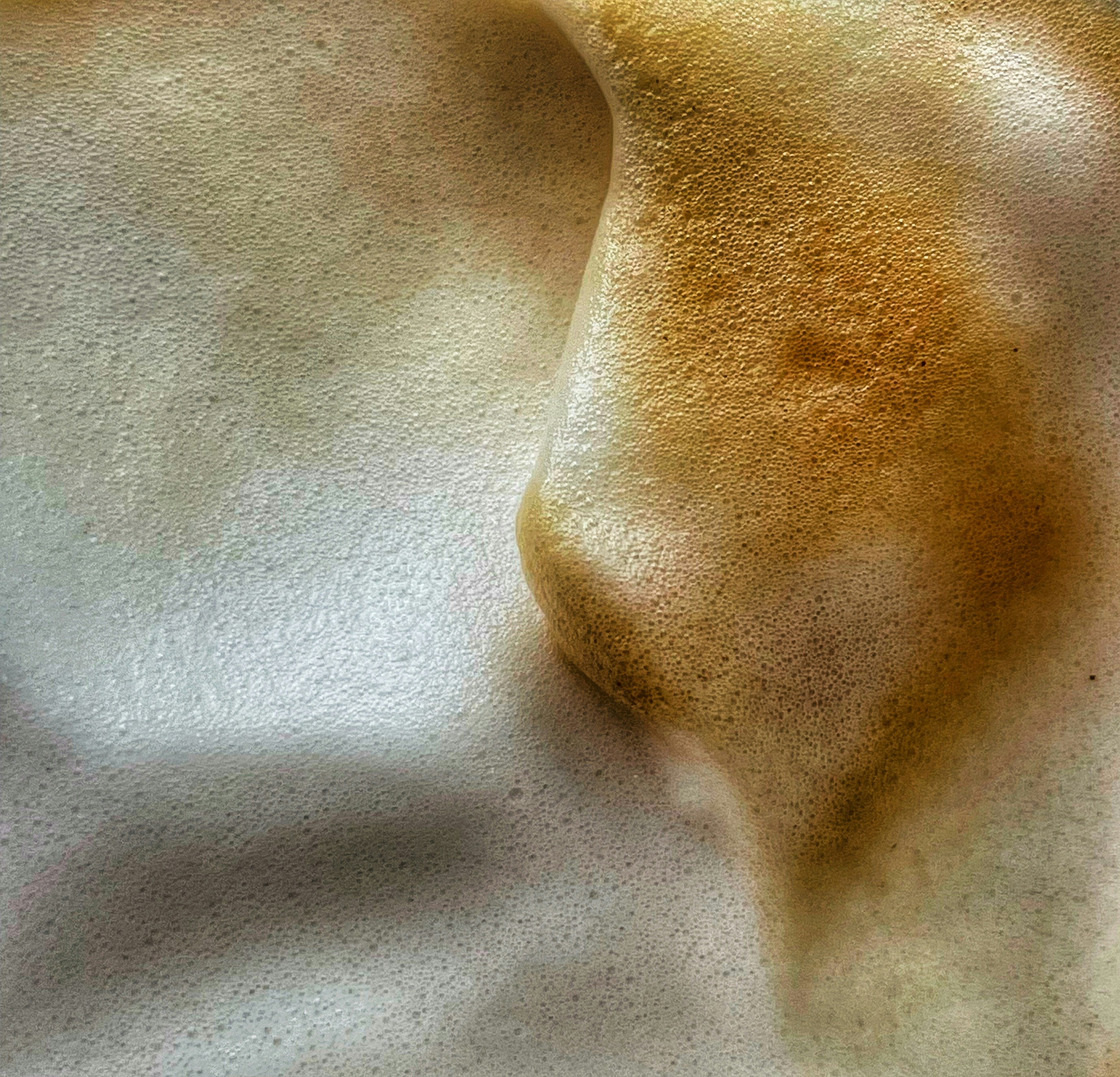 Close-up of frothy surface revealing intricate patterns and warm hues, highlighting a blend of textures and colors.