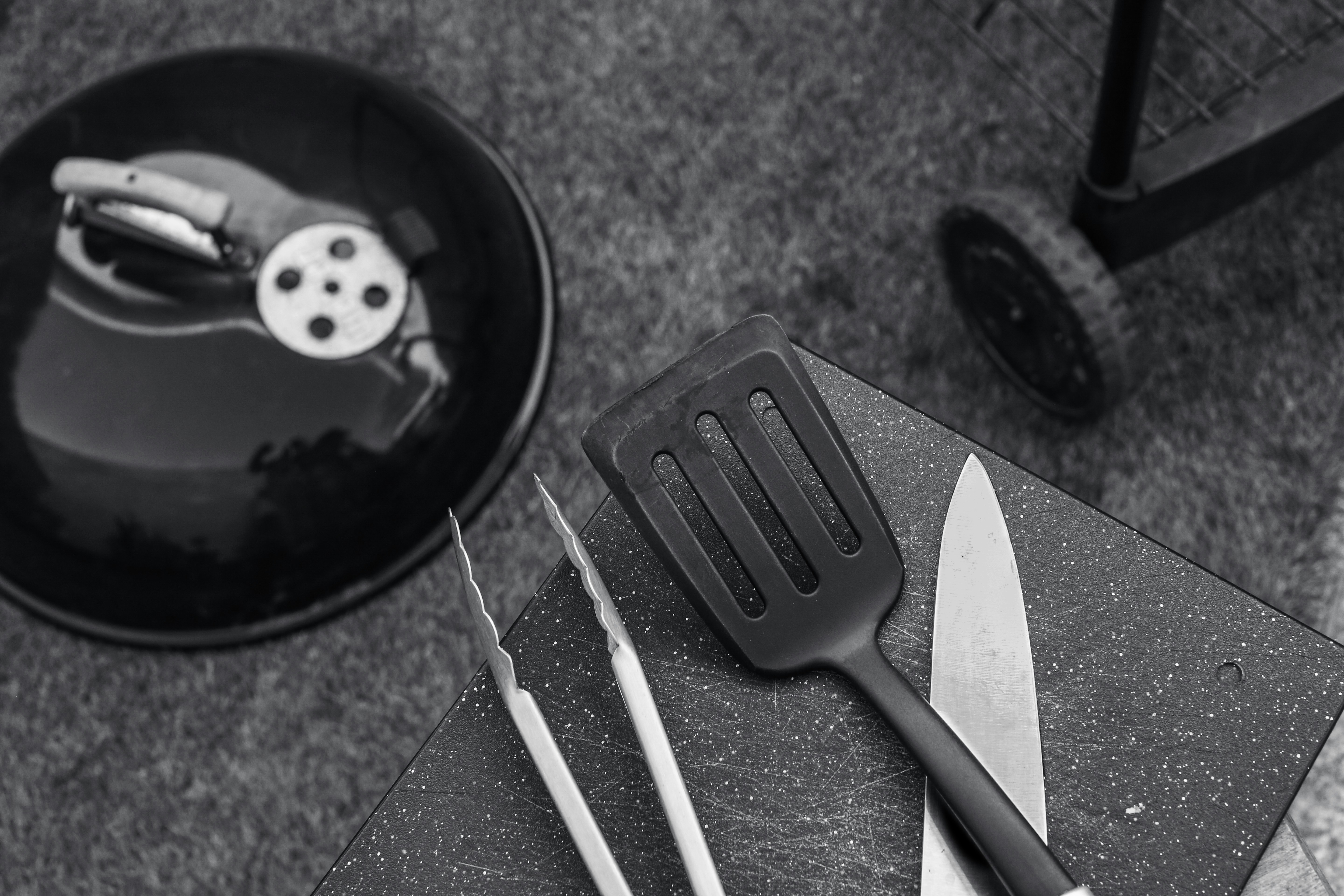Monochrome Grill Tools Angled Across a Speckled Cutting Board