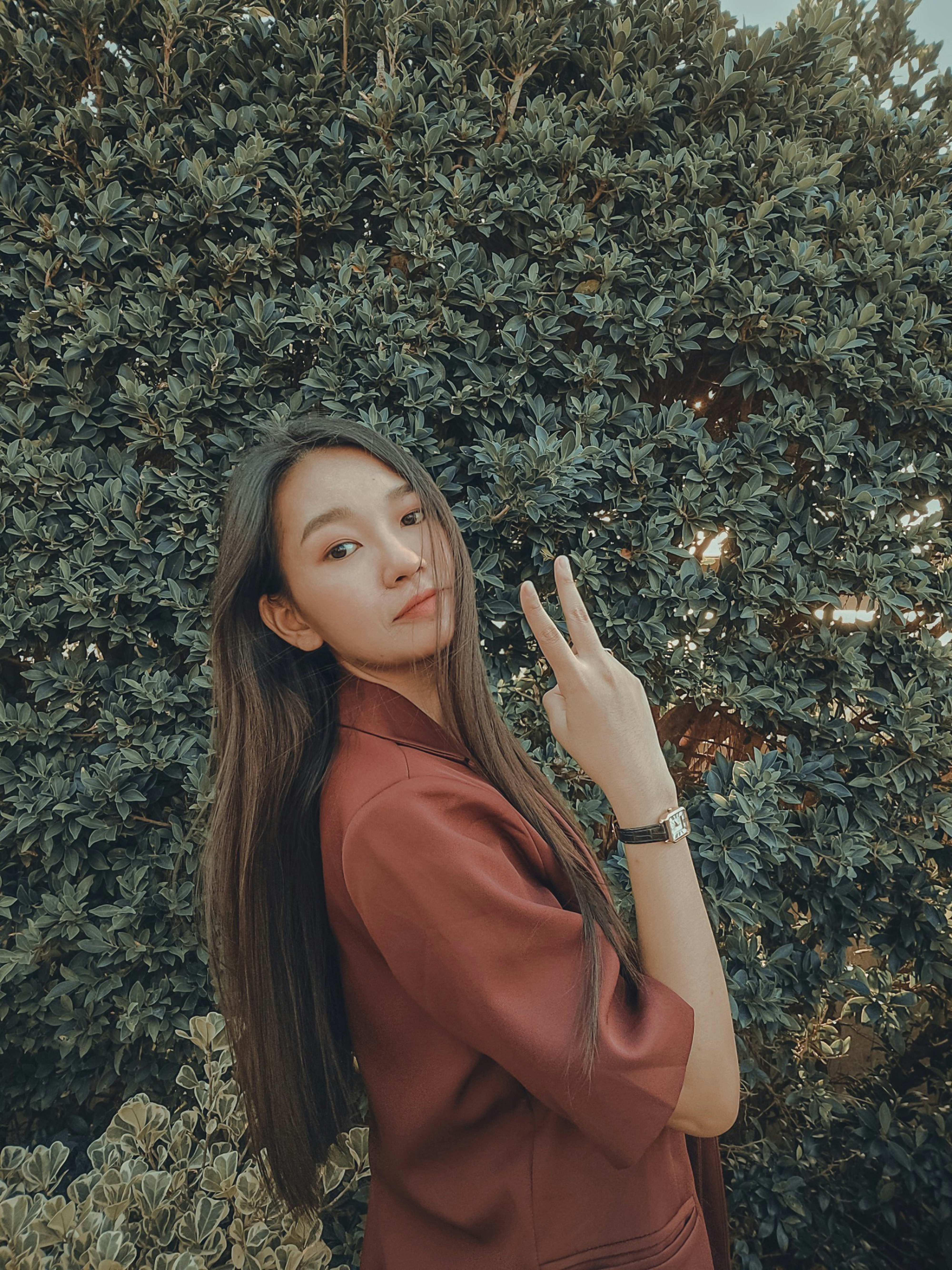 A woman standing in front of a bush holding a cell phone photo – Free ...