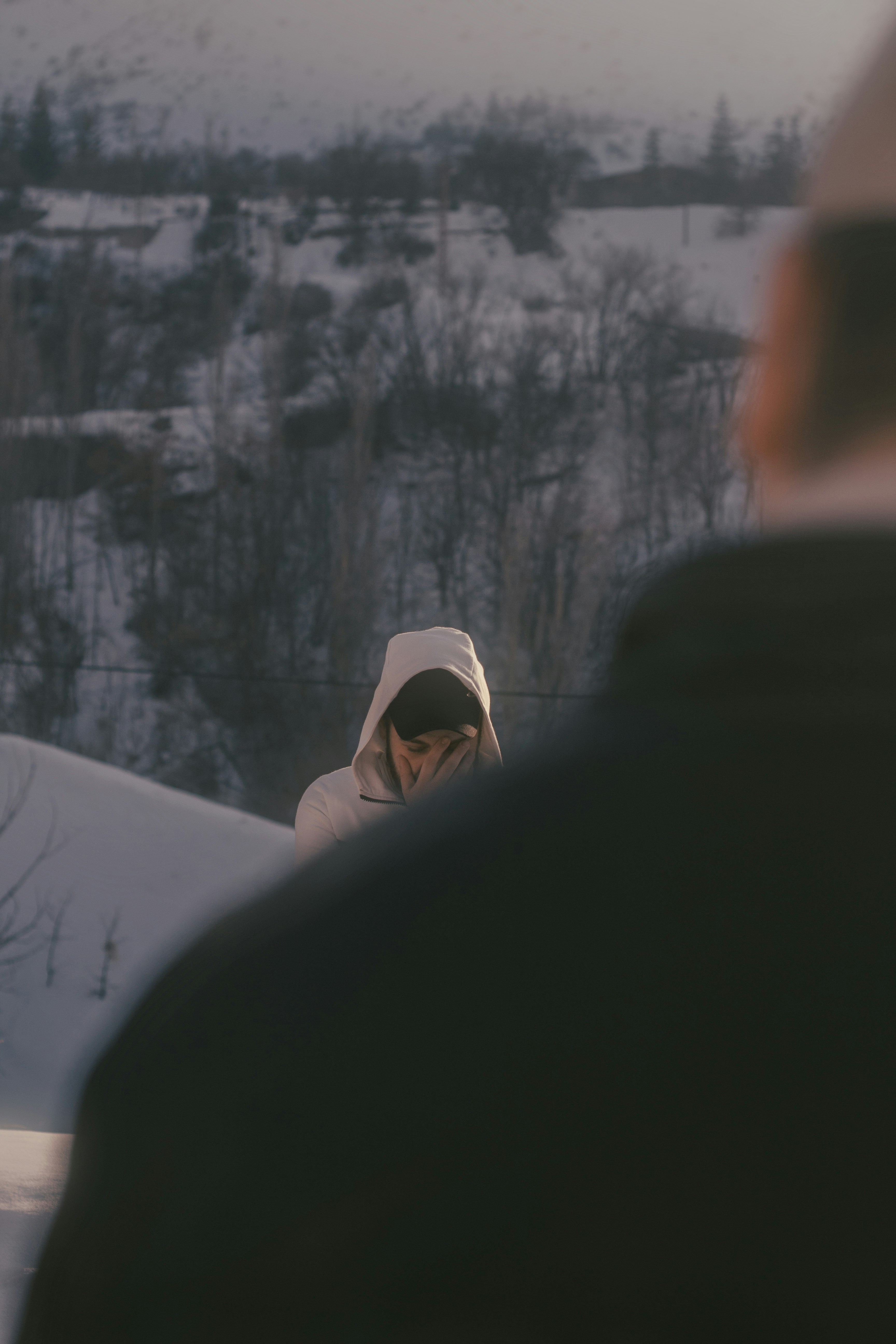 a man in a hoodie looking out over a snowy landscape
