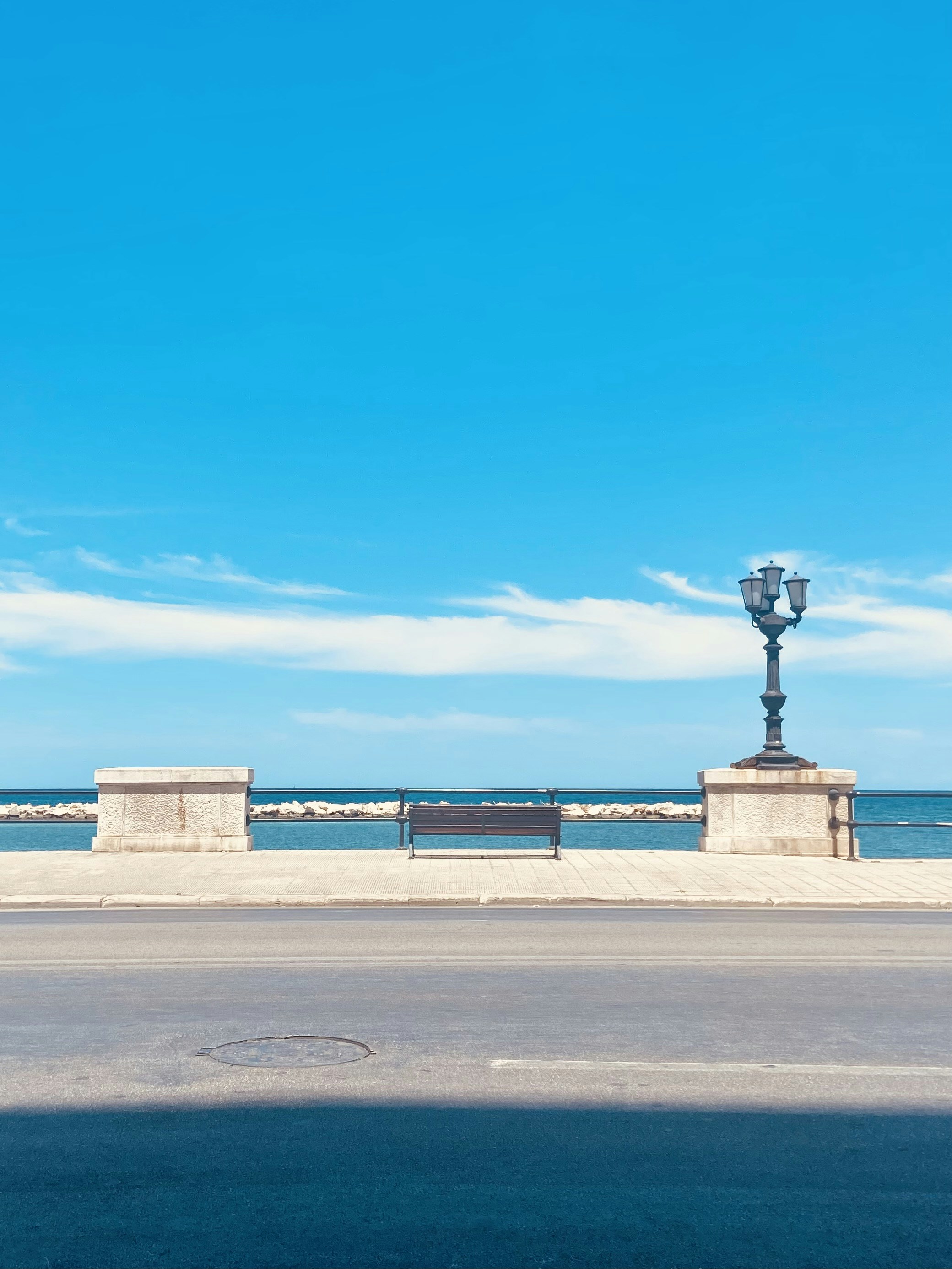 An empty bench on a coast road in Bari, Italy. 