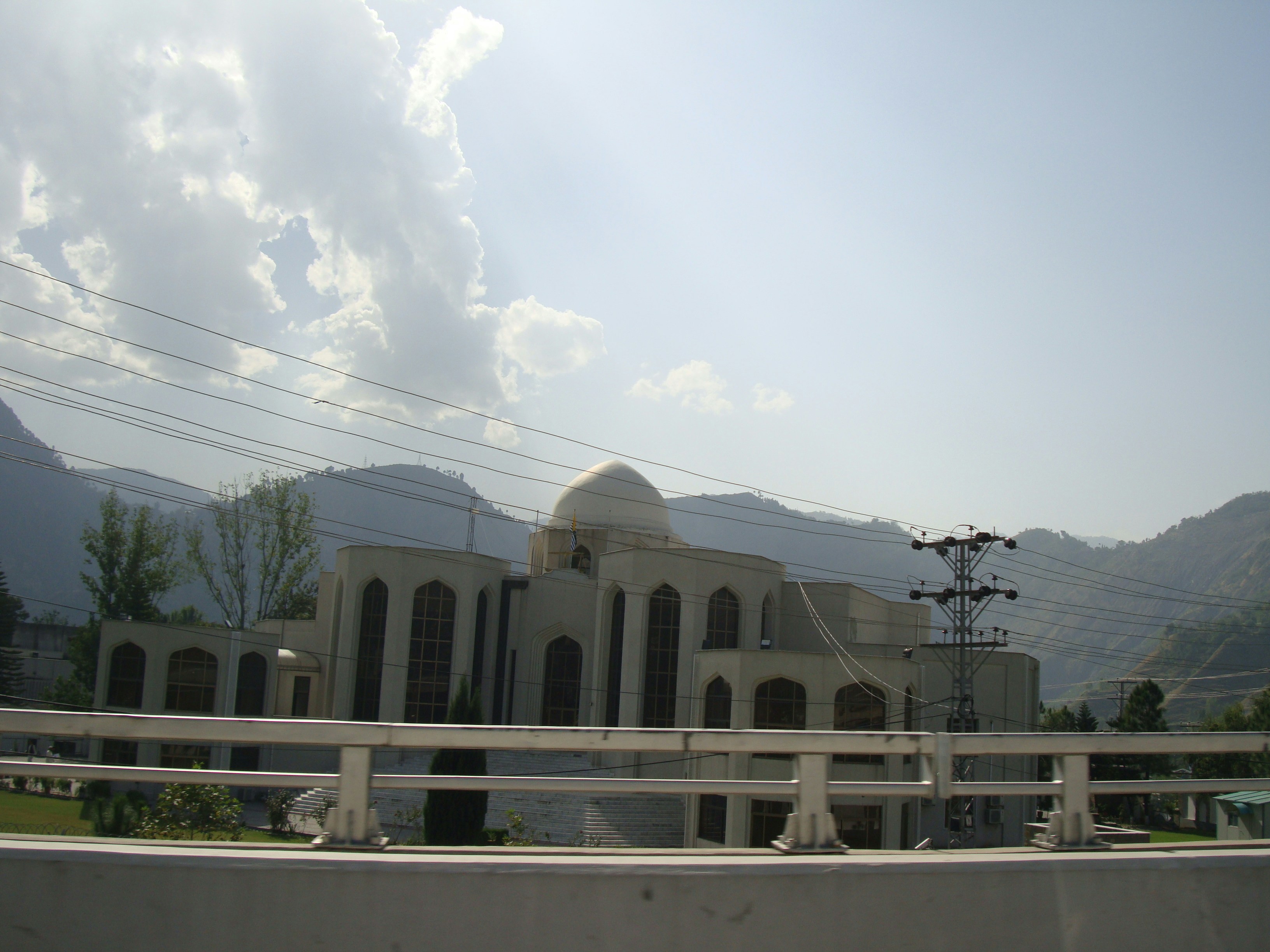 A modern building nestled in a mountainous landscape, showcasing elegant architecture against a backdrop of rolling hills and dramatic skies.