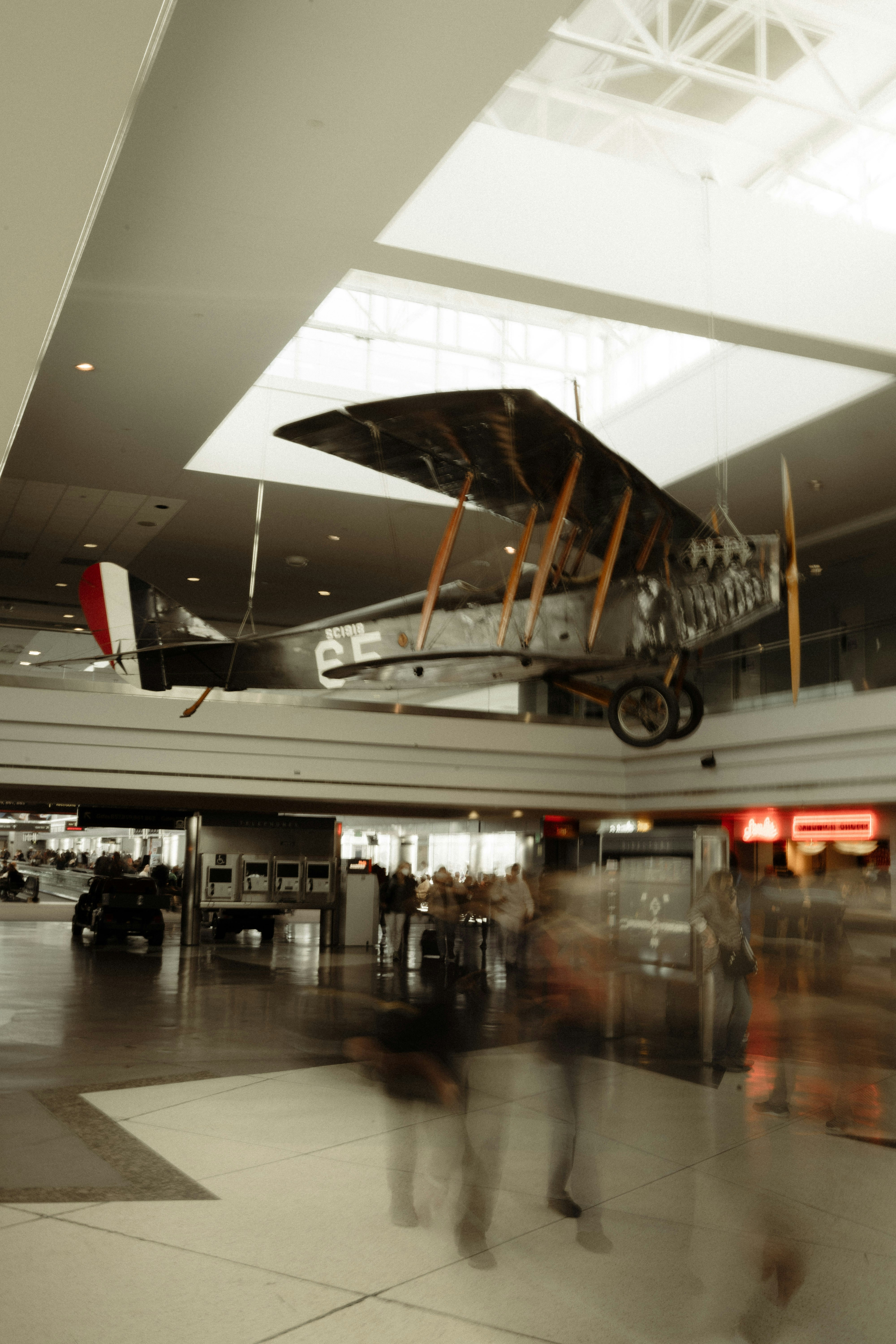 Hovering Relic: A Vintage Biplane Above a Lively Atrium