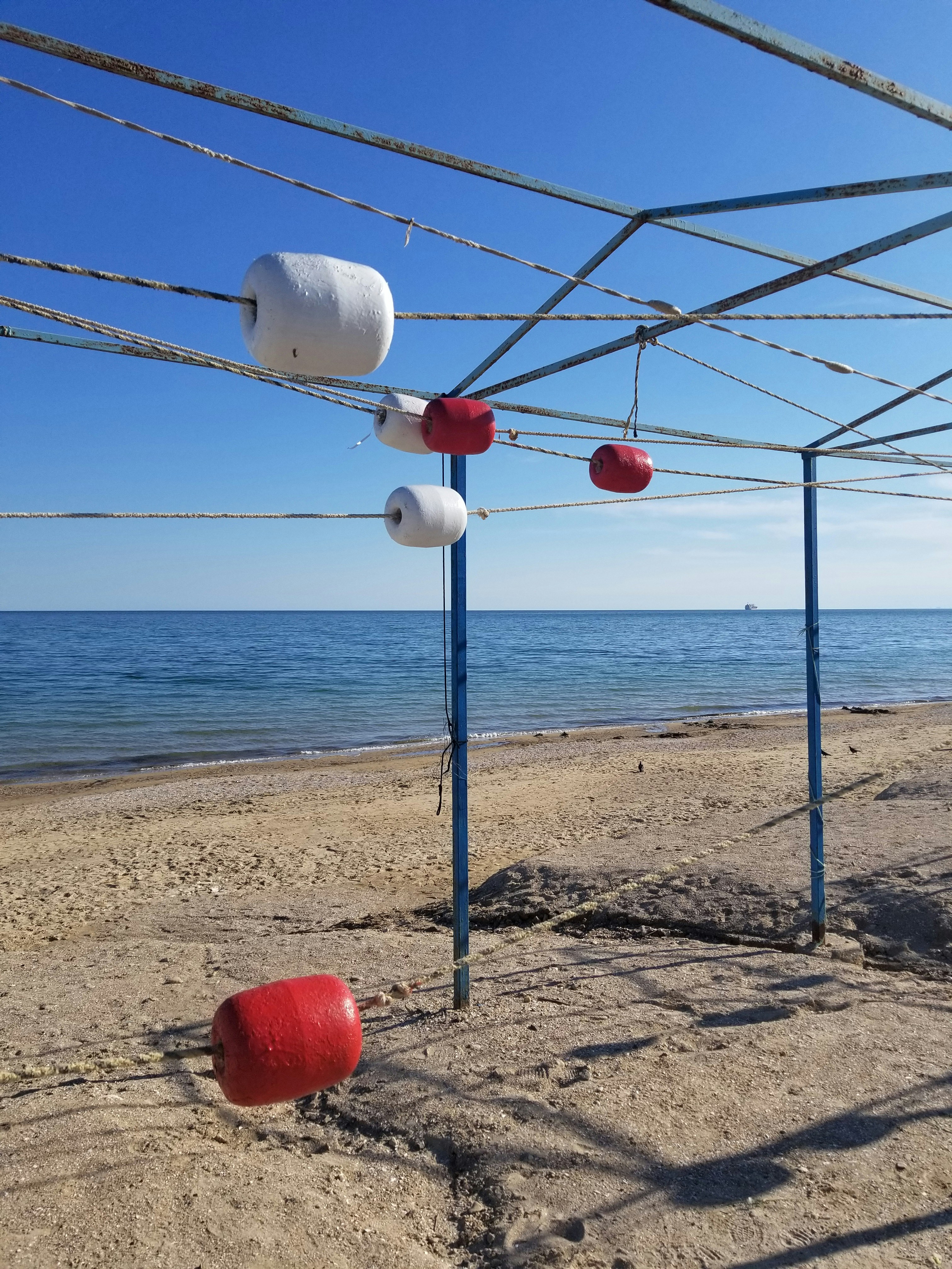 A sandy beach with blue poles and red and white balls photo – Free ...