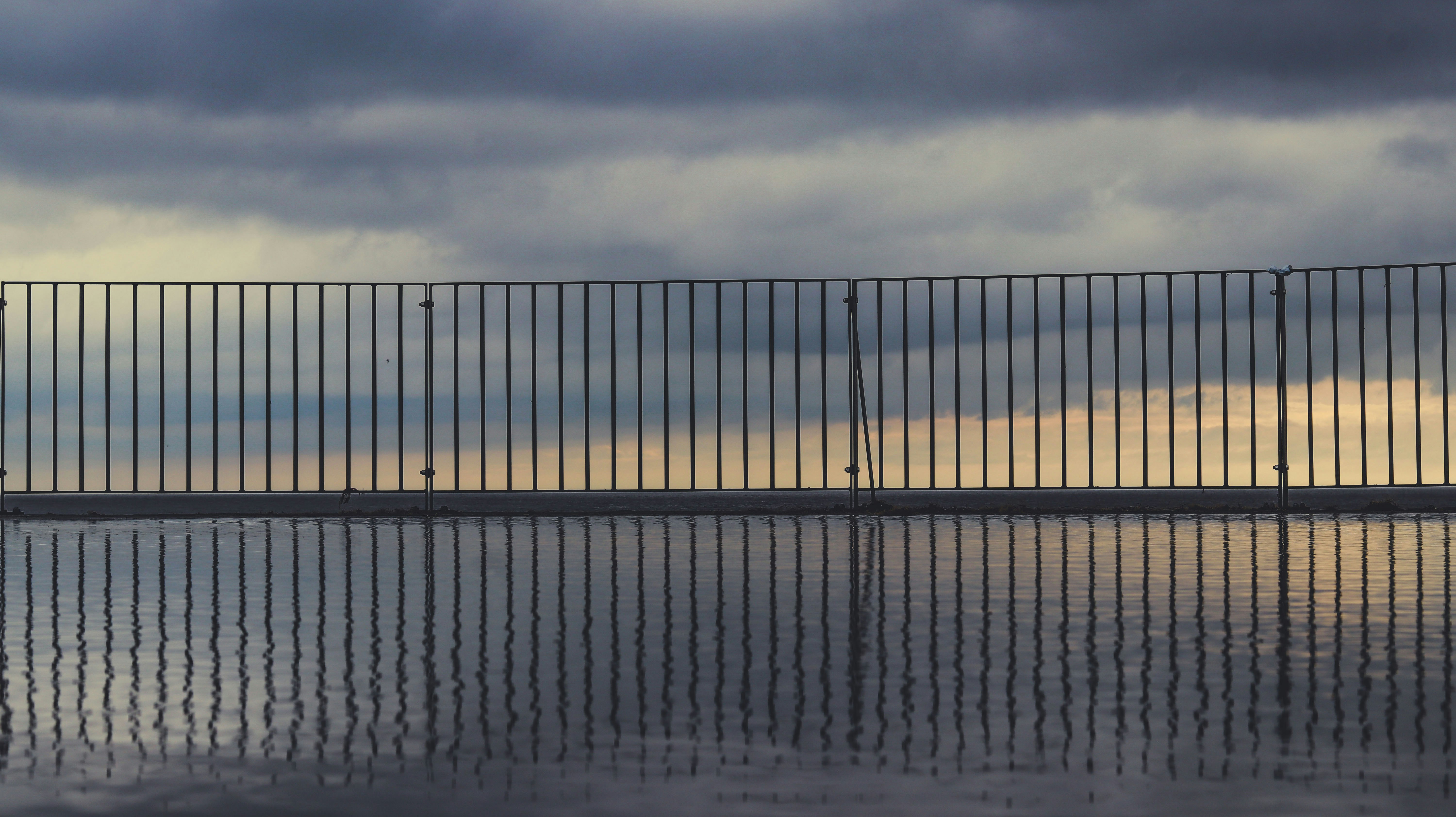 Railing Across a Glassy Horizon: Reflections Trace a Quiet Waterfront