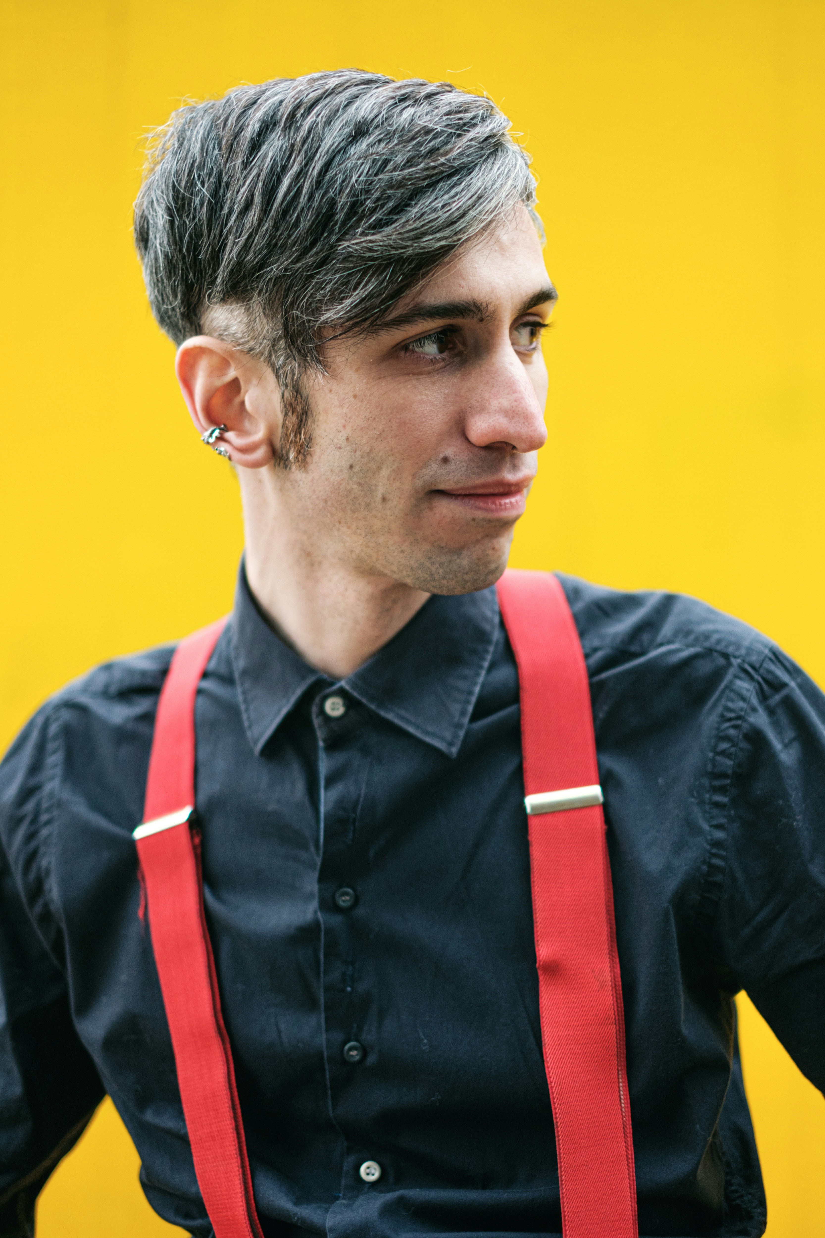 Yellow Backdrop, Steel-Grey Gaze: Portrait of a Man in Red Suspenders