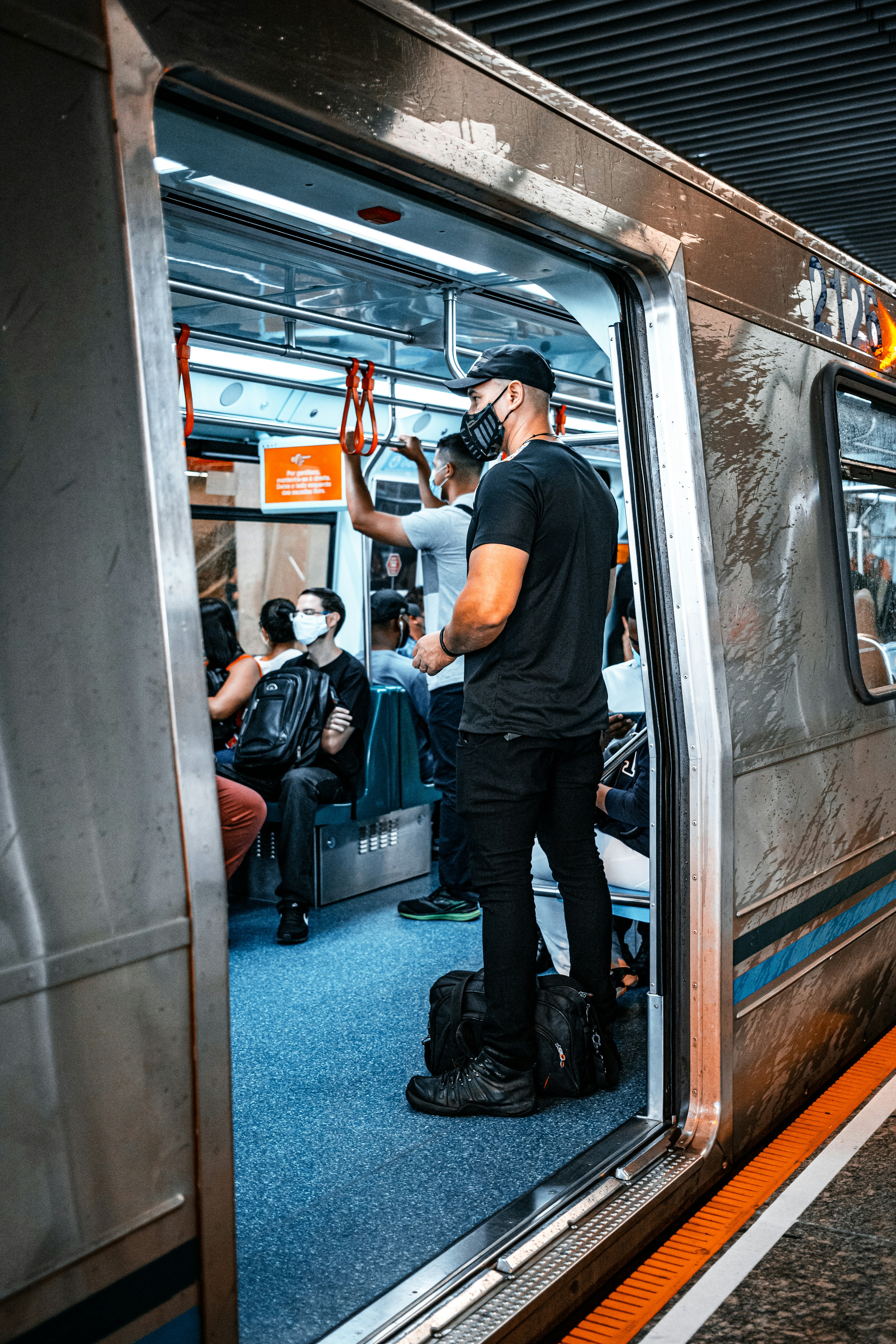 At the Subway Threshold: a masked commuter anchors the doorway as passengers fill the car