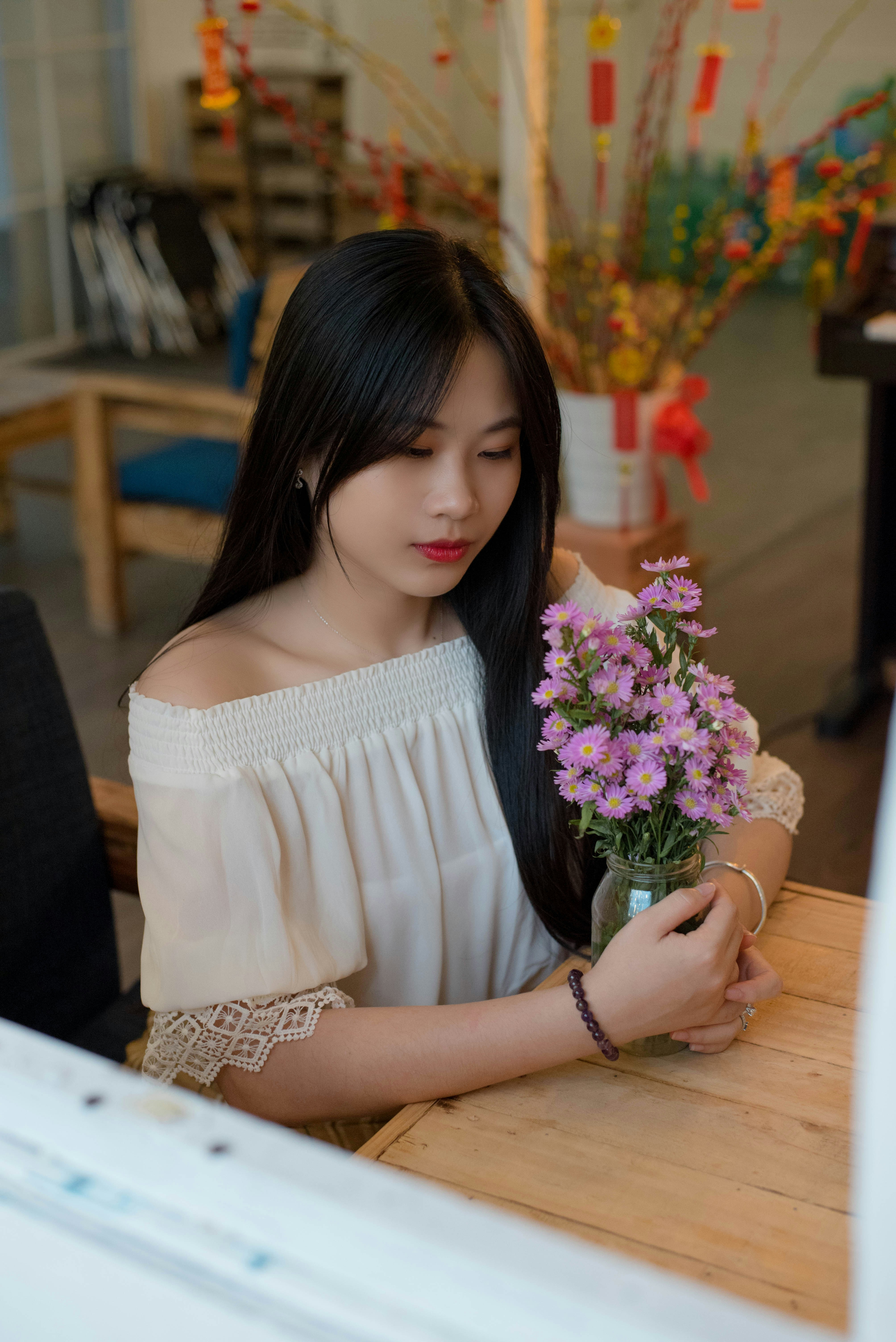 Una mujer sentada en una mesa sosteniendo un ramo de flores foto – Imagen de Persona gratuita en ...