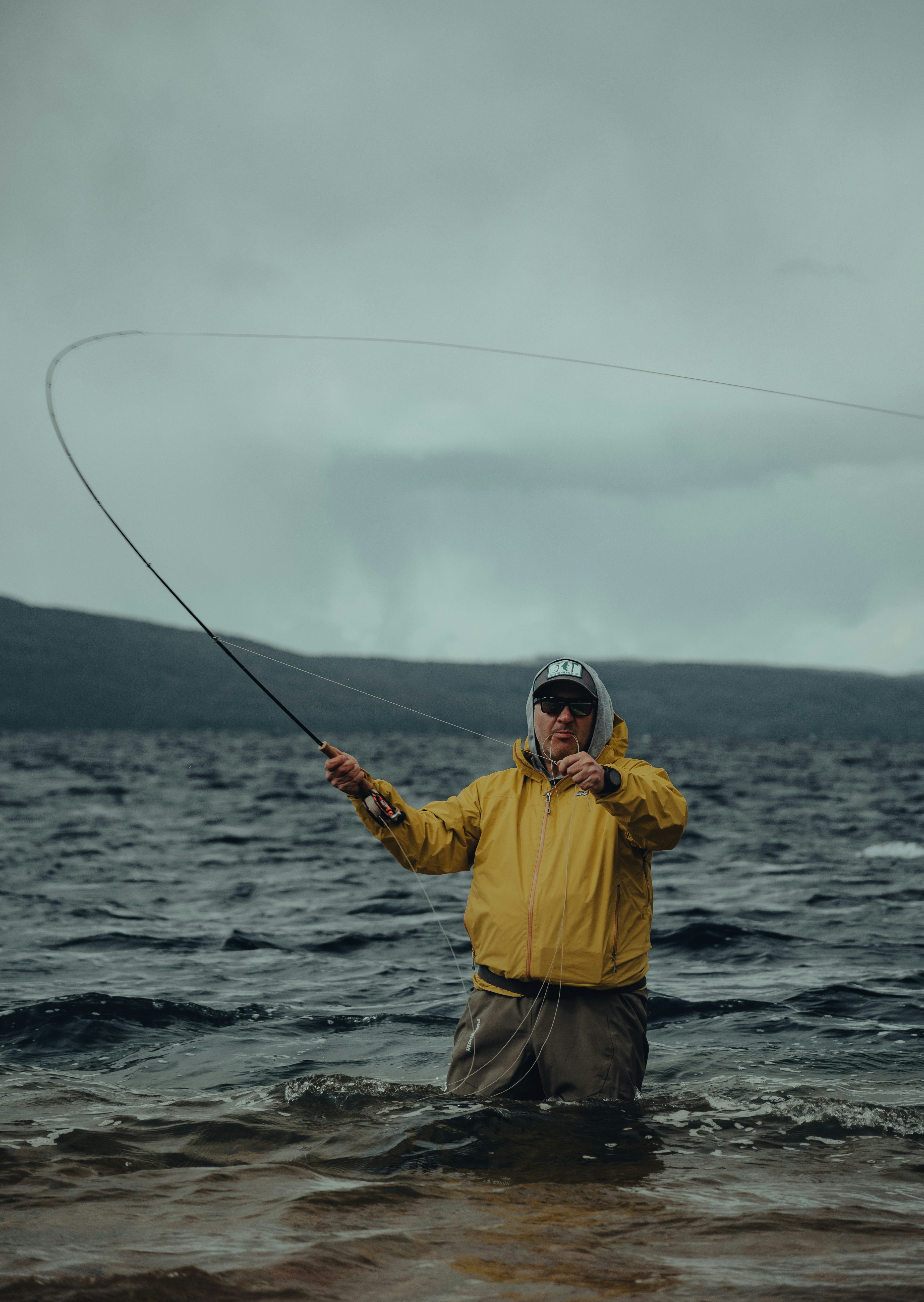A man standing in the water while holding a fishing rod photo – Free ...