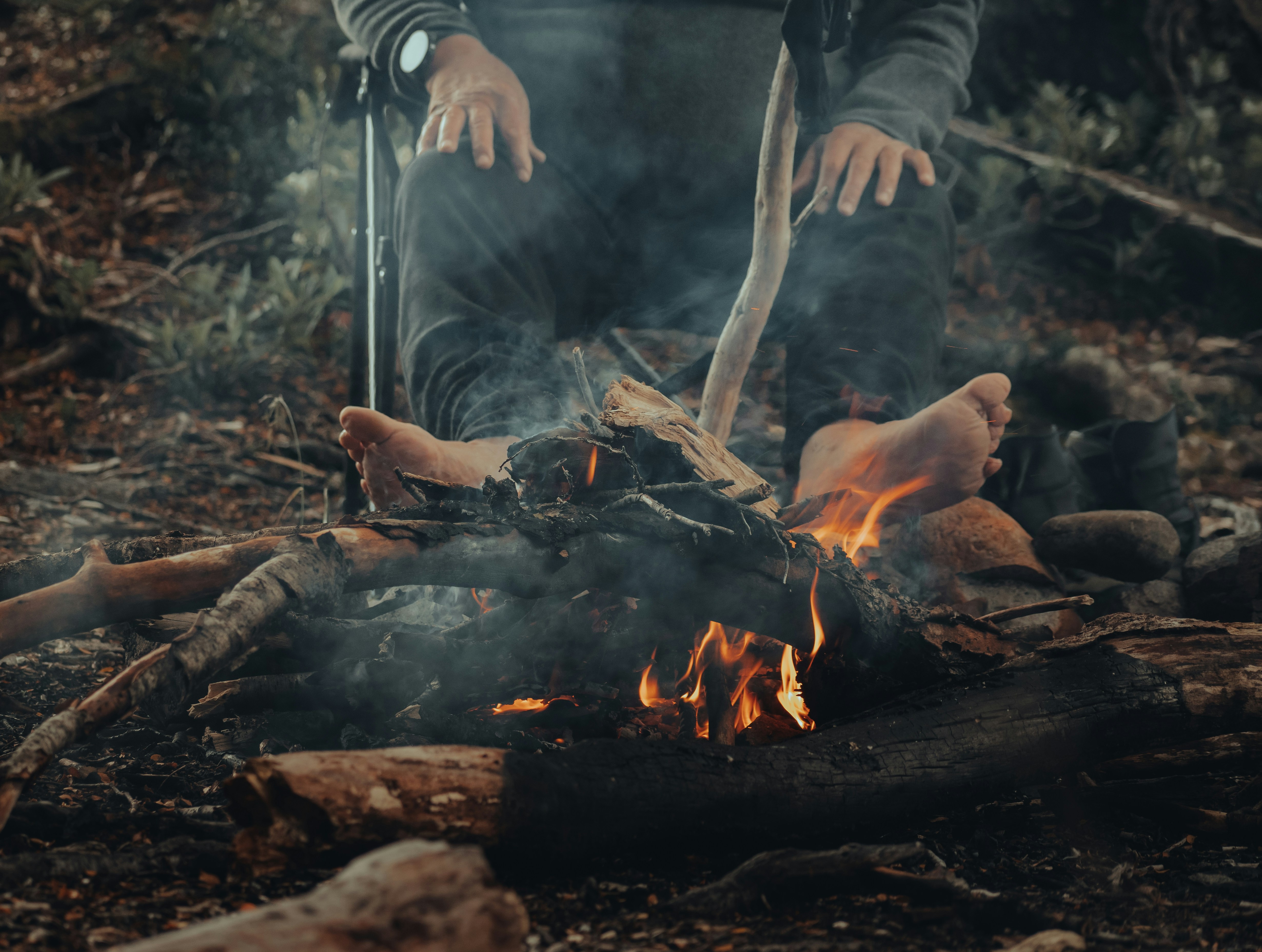 A person standing over a fire in the woods photo – Free Grey Image on ...