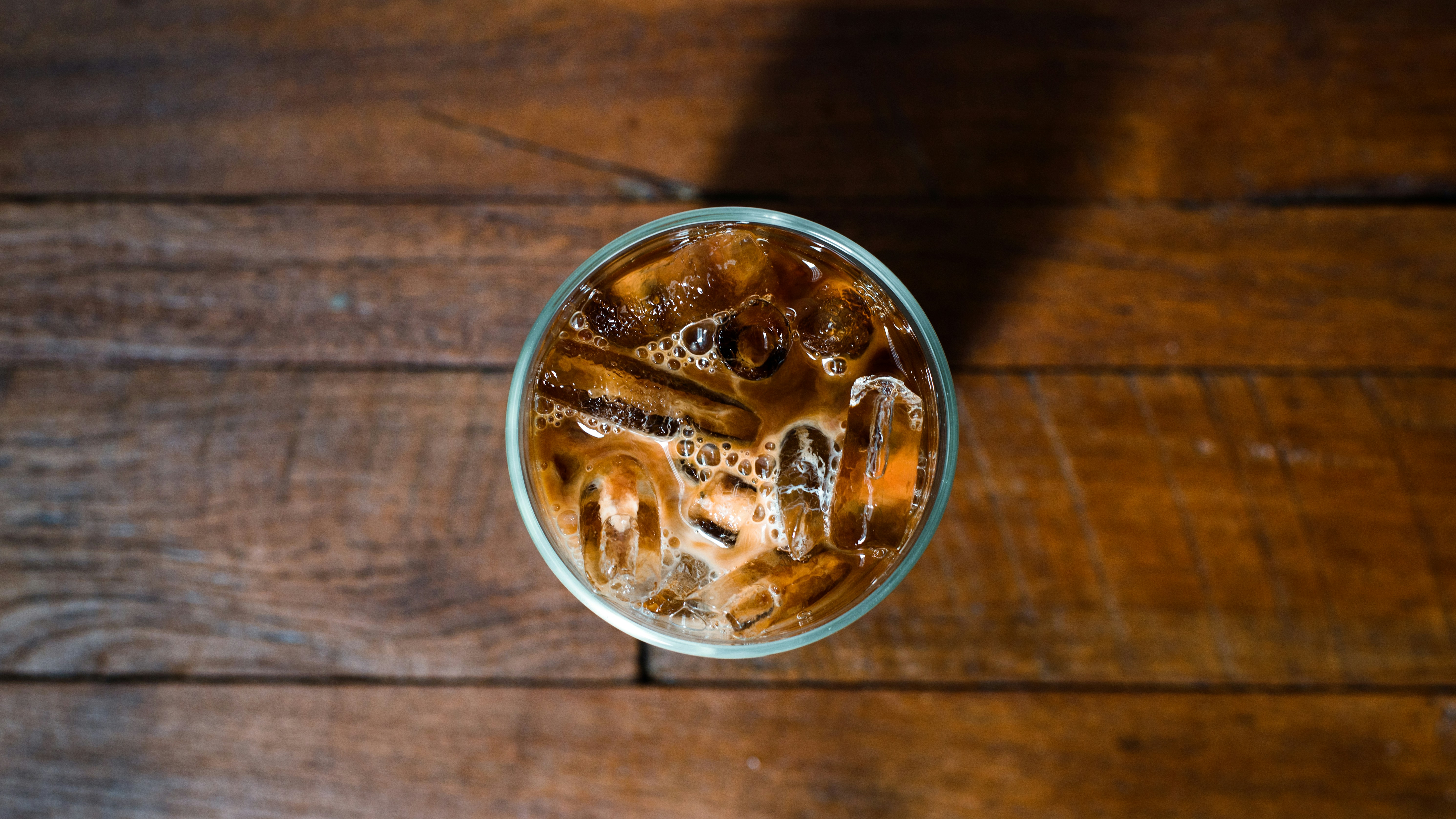Overhead Amber: Ice Cubes Framing a Coffee on Rustic Wood