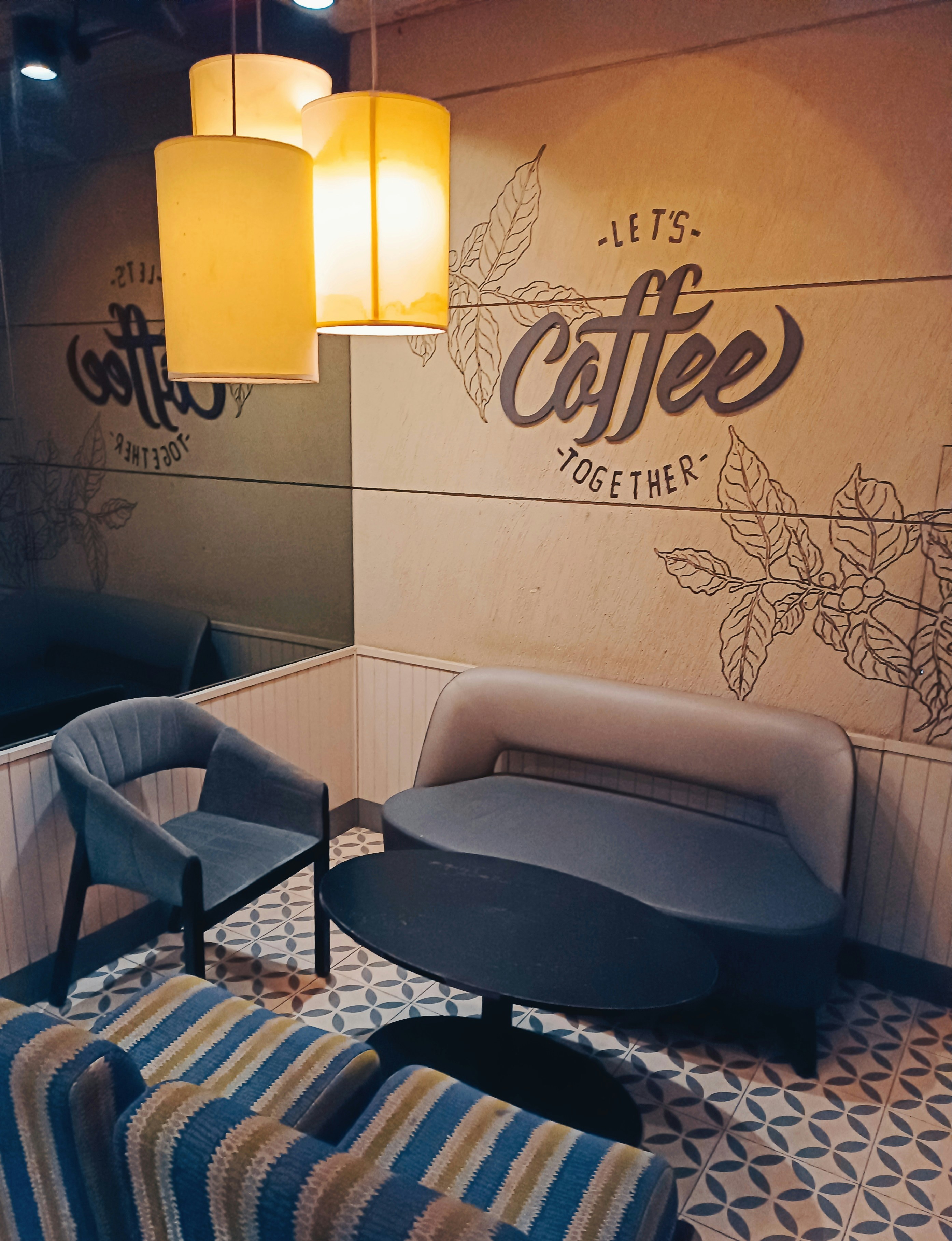 Inviting café nook with modern seating and warm lighting under a mural that reads 'Let's Coffee Together.'