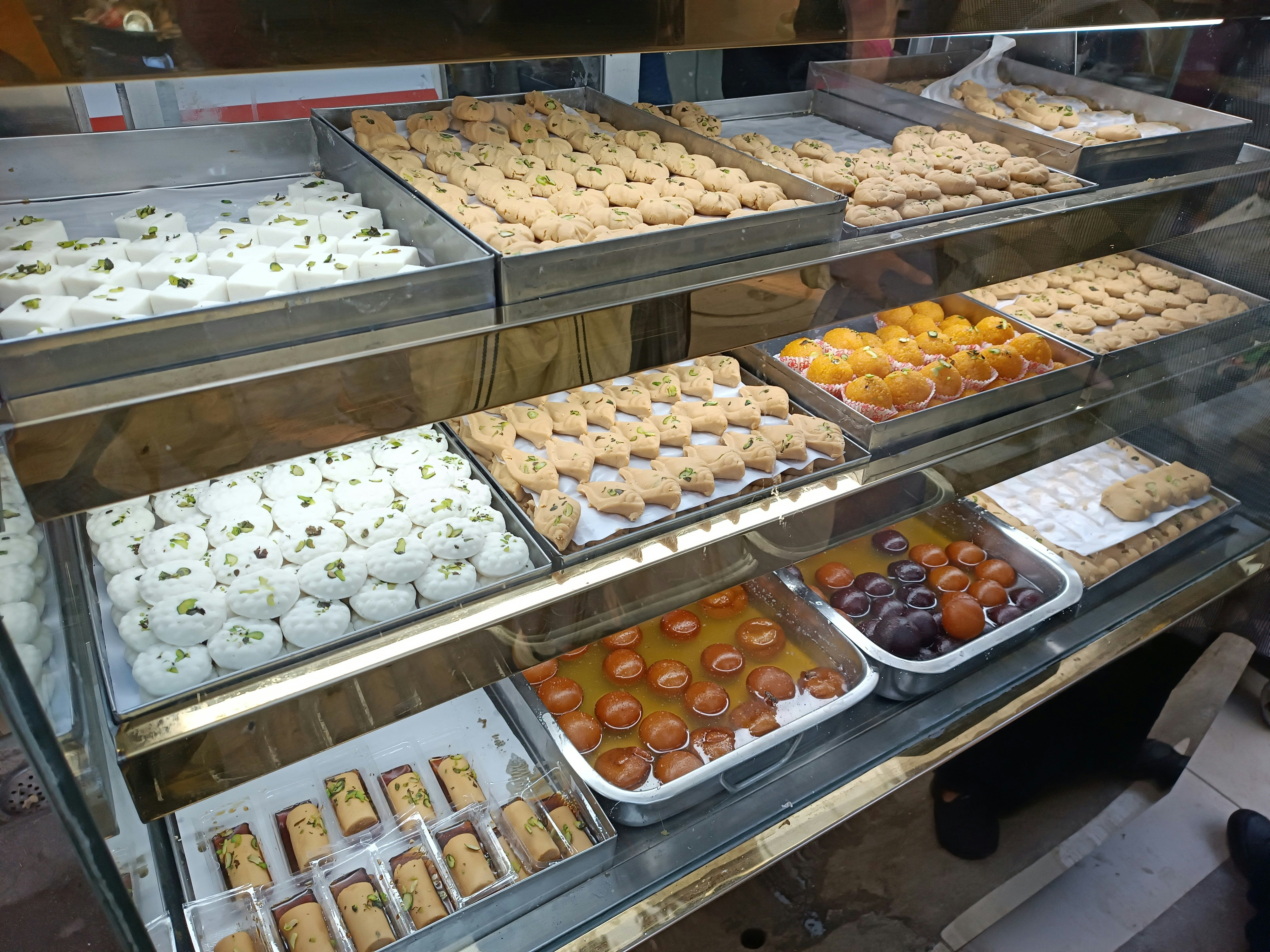 Assorted sweets neatly arranged in a glass display case at a shop.