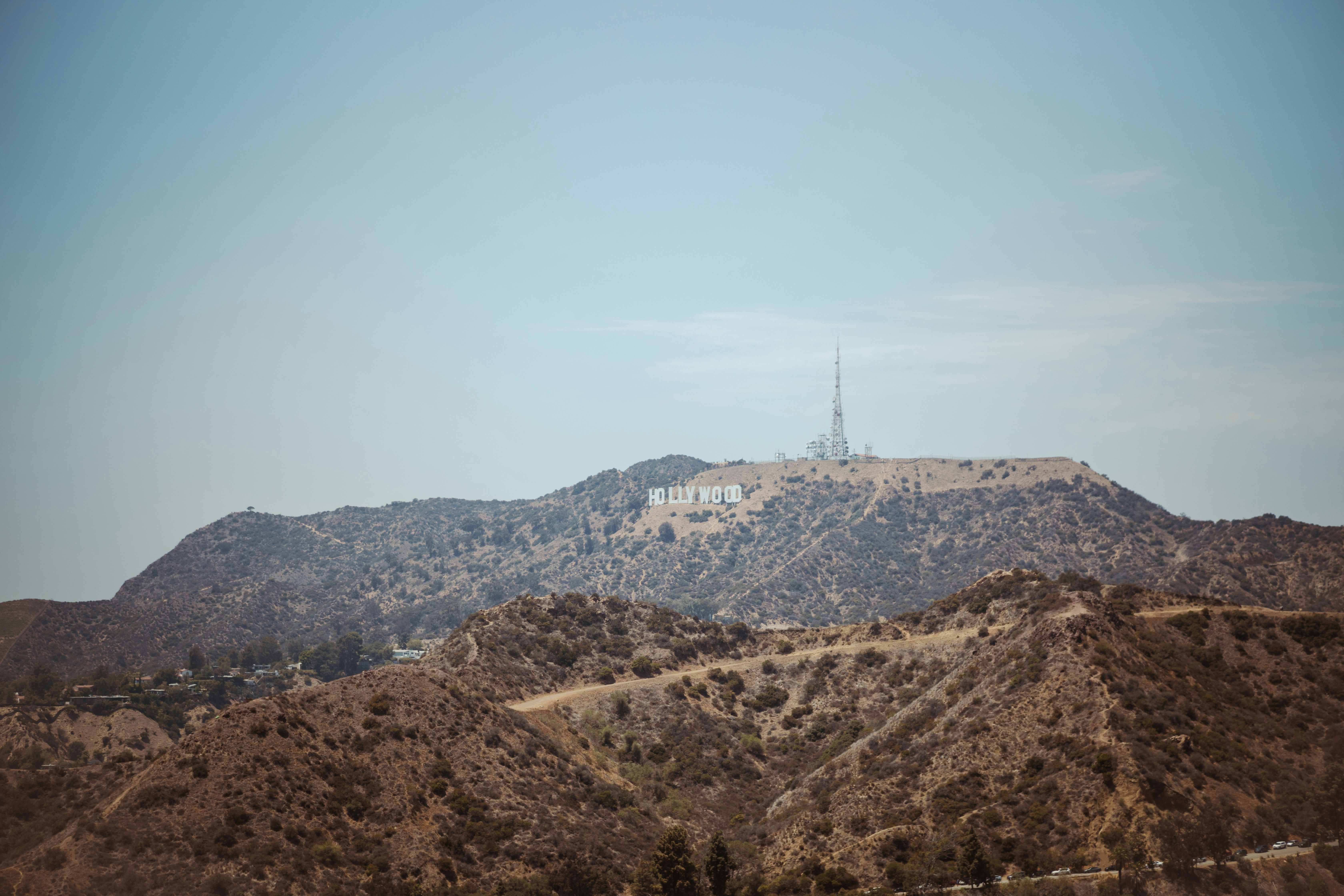 Hollywood sign perched atop the hills, surrounded by rugged terrain and a clear blue sky.