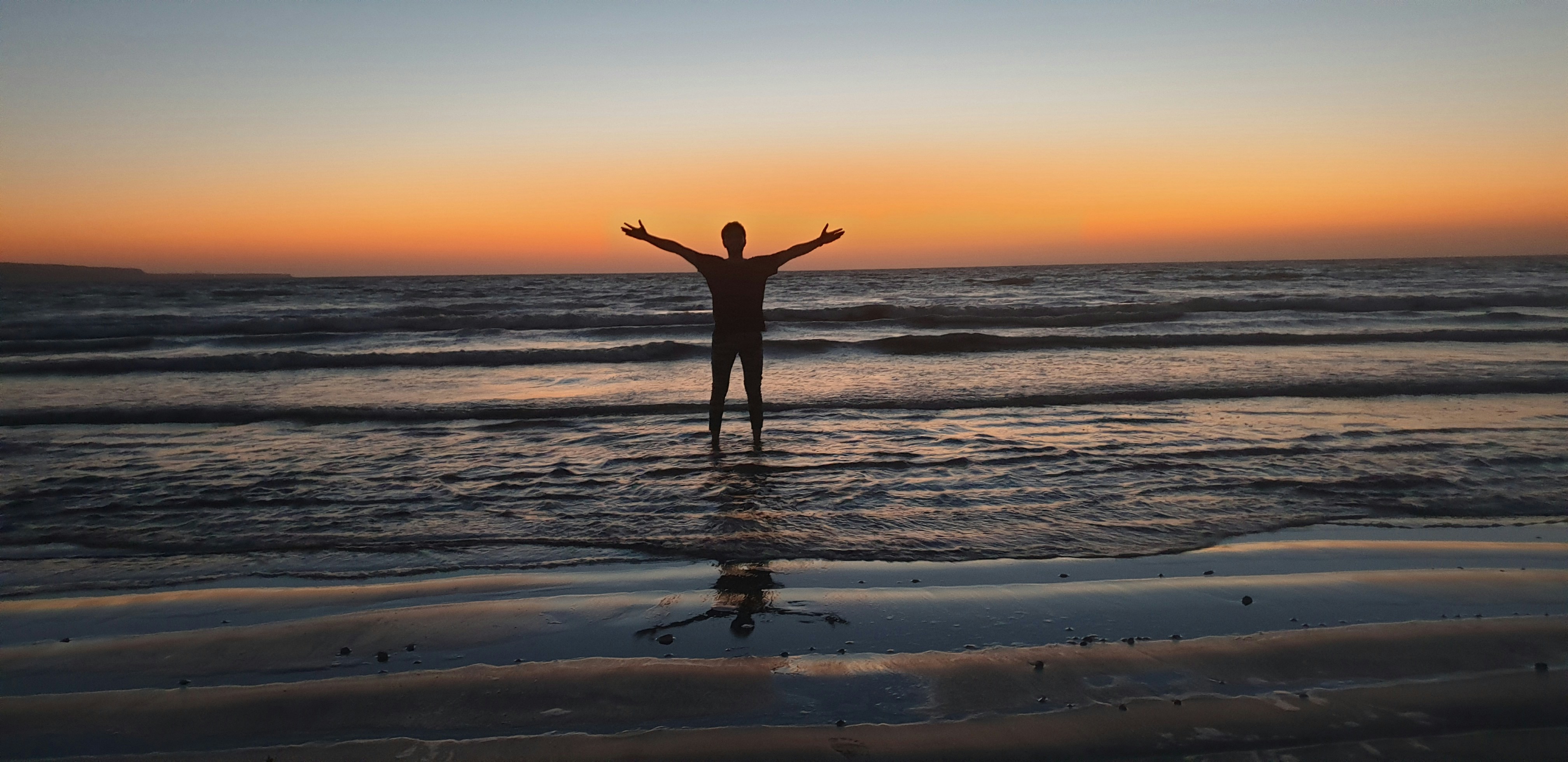 a person standing on a beach at sunset