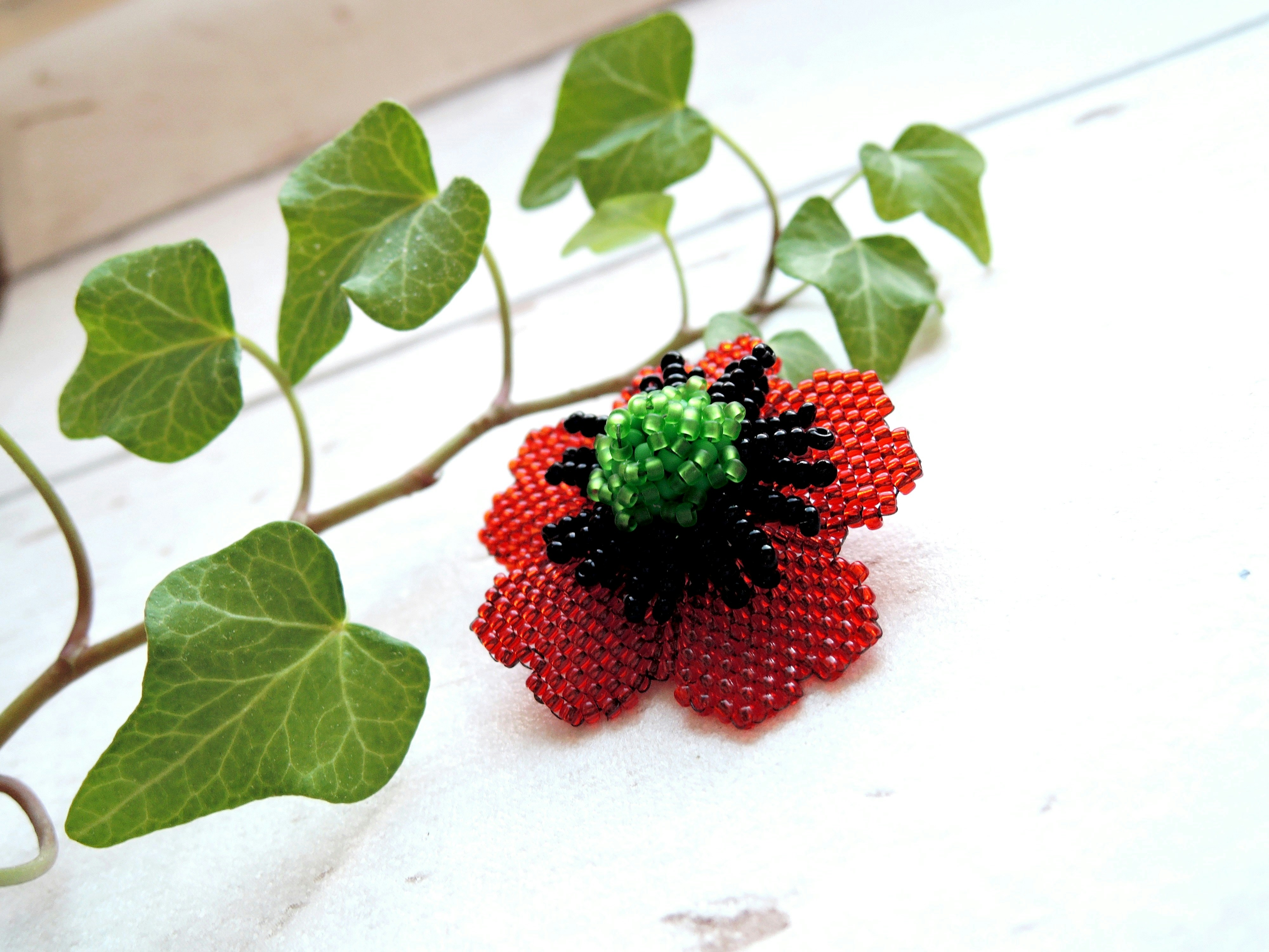 A red beaded flower sitting on top of a white table photo – Free Leaf ...