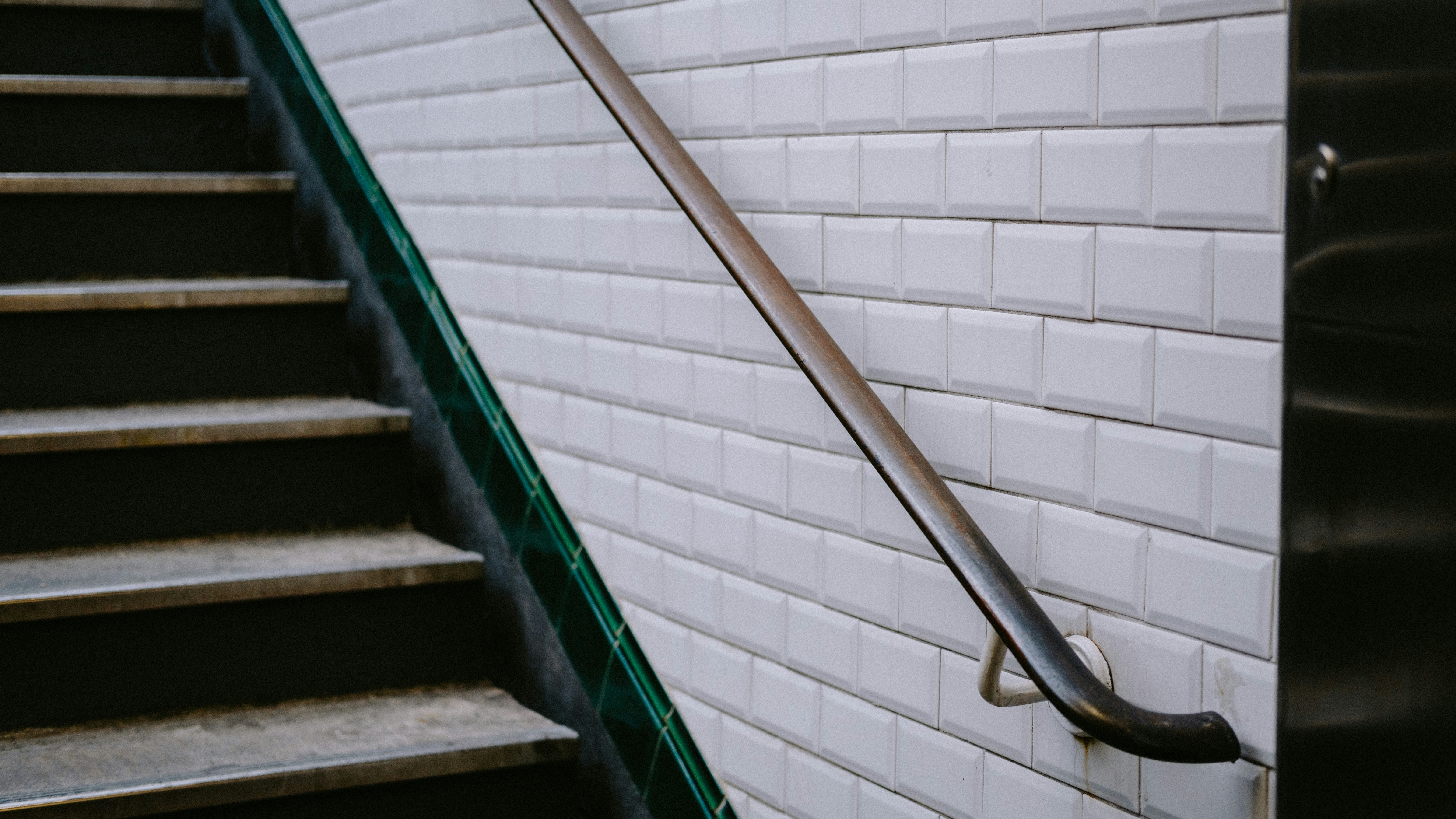 Iron Ribbon in a Stairwell: Geometry and Light on White Tiles