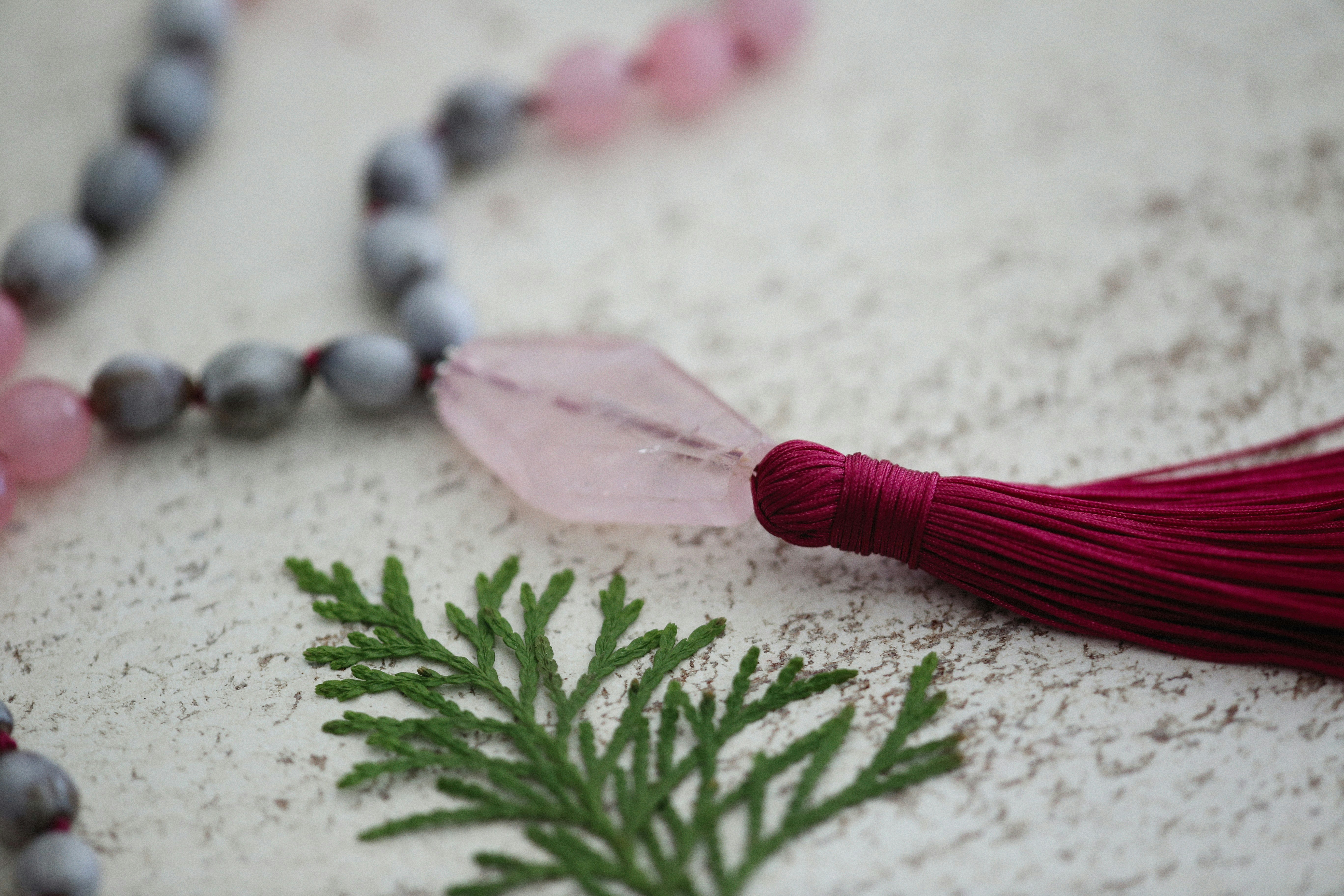 Un collier à tasseaux avec des perles roses et un gland rouge photo ...