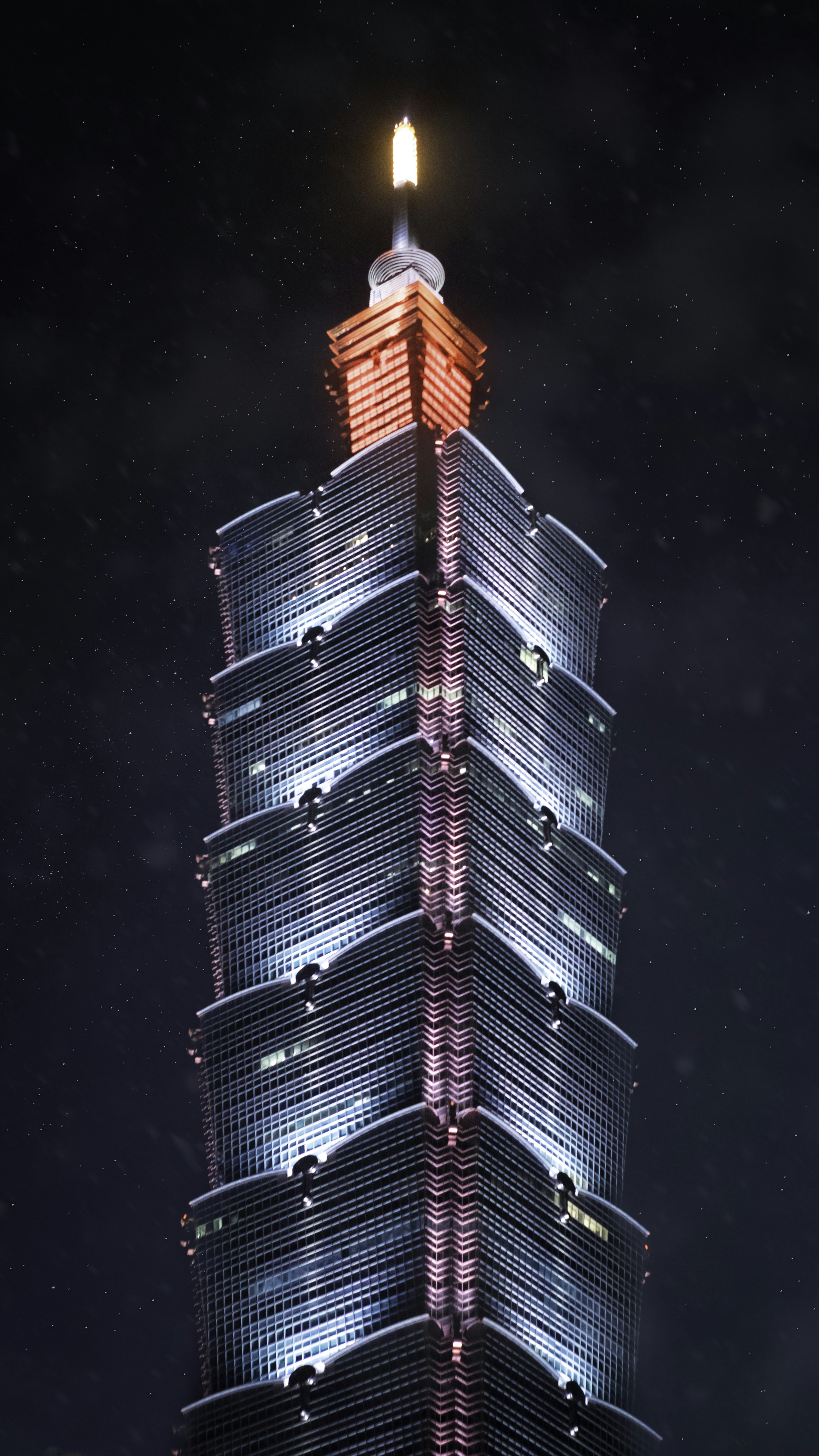 Taipei 101 pierces the night sky, adorned with vibrant lights reflecting its architectural grandeur.
