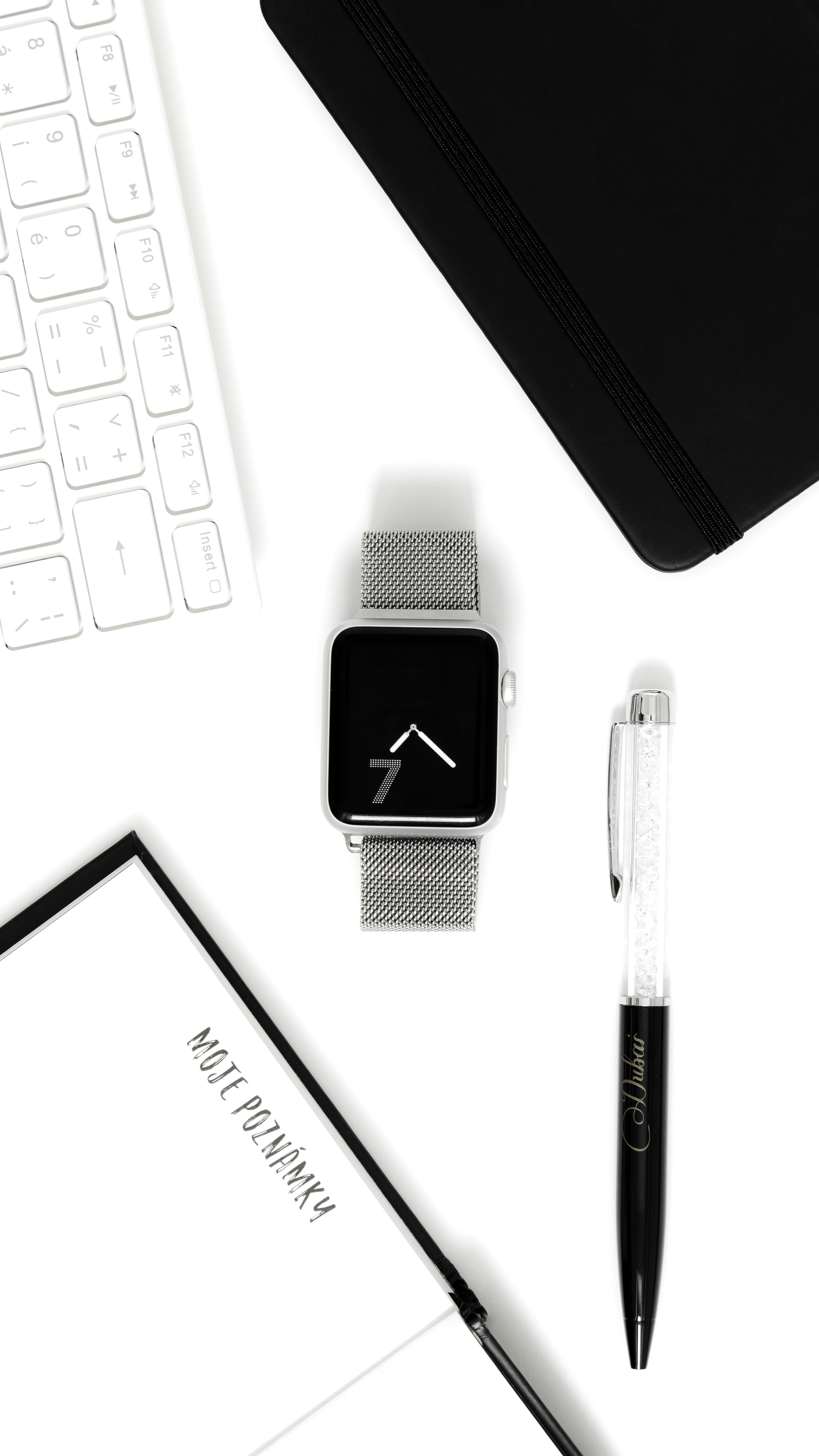 A desk with a keyboard, watch, pen and paper photo – Free Keyboards ...