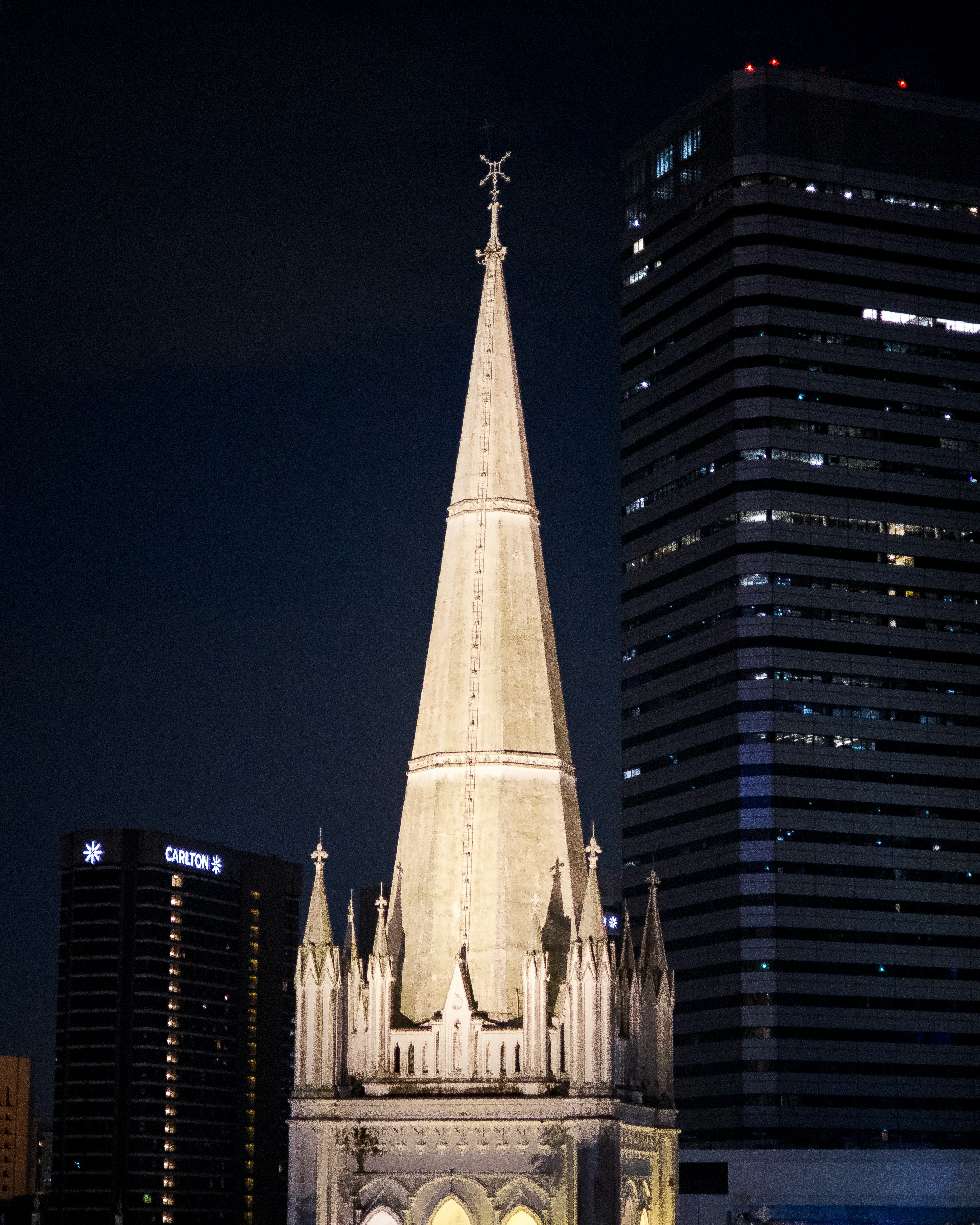a church steeple lit up at night in a city