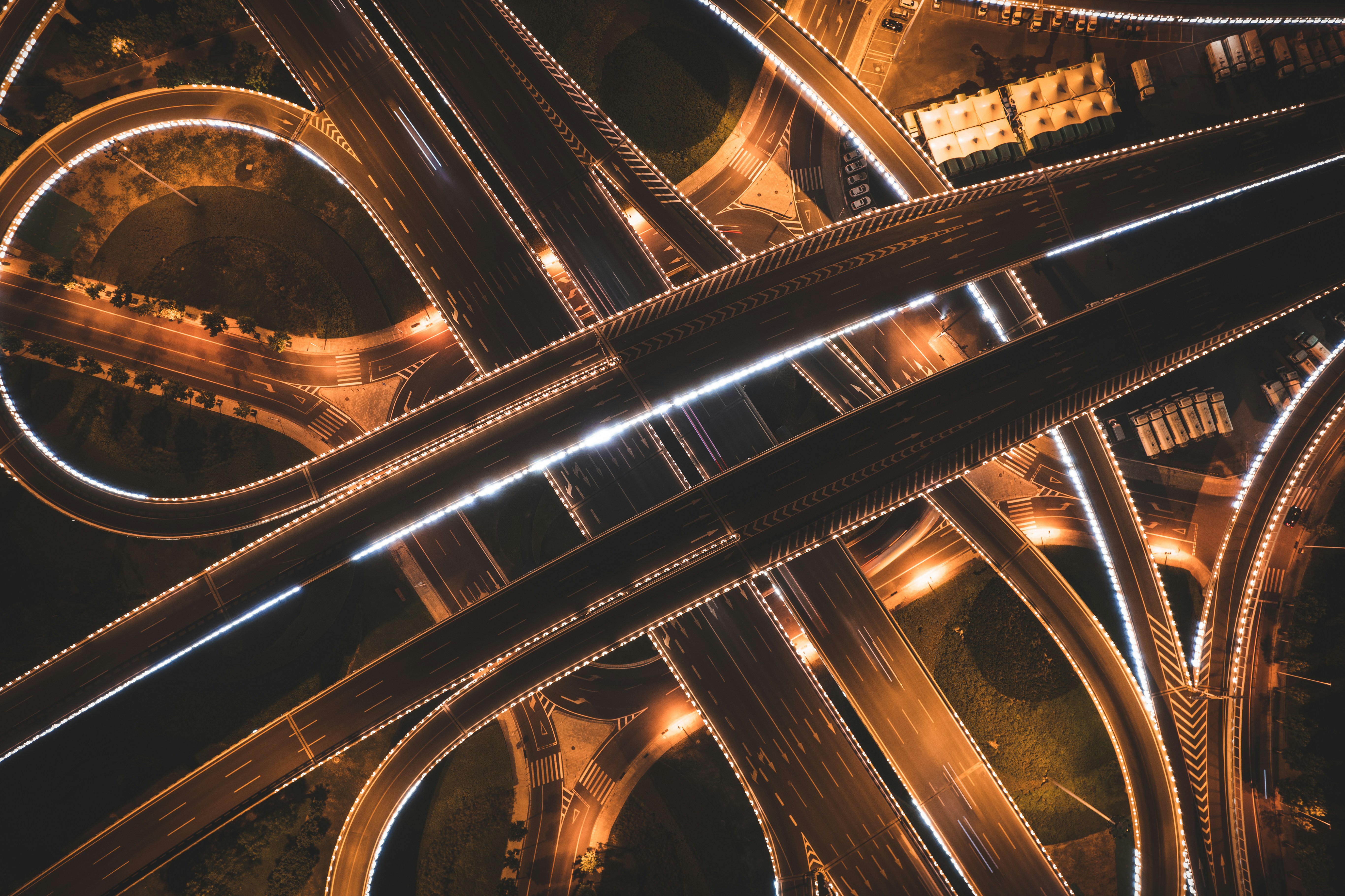 Intricate network of illuminated highways intertwining in a complex urban landscape at night.