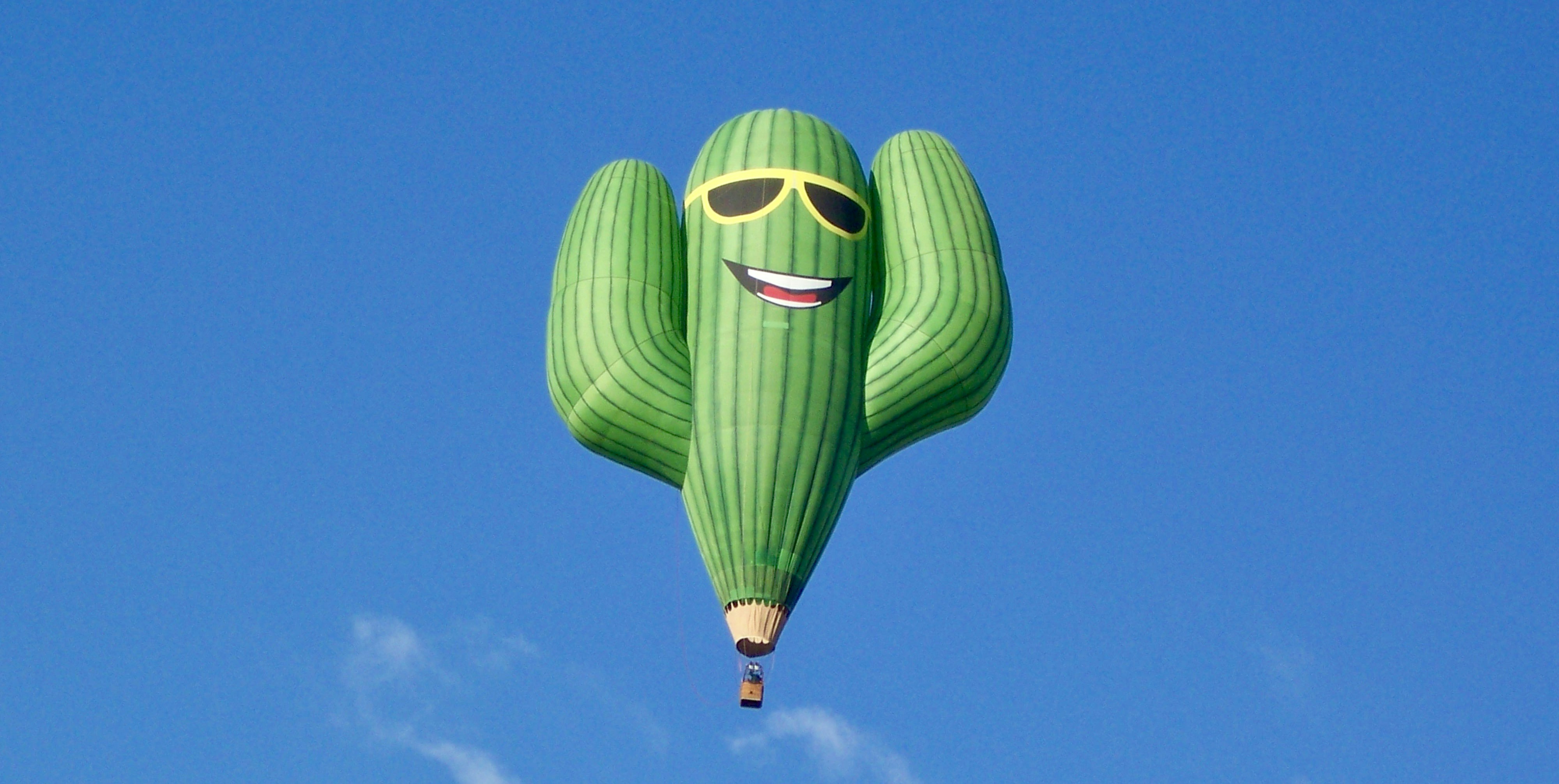 Sunglasses-Wearing Cactus Balloon Drifts Under a Clear Blue Sky