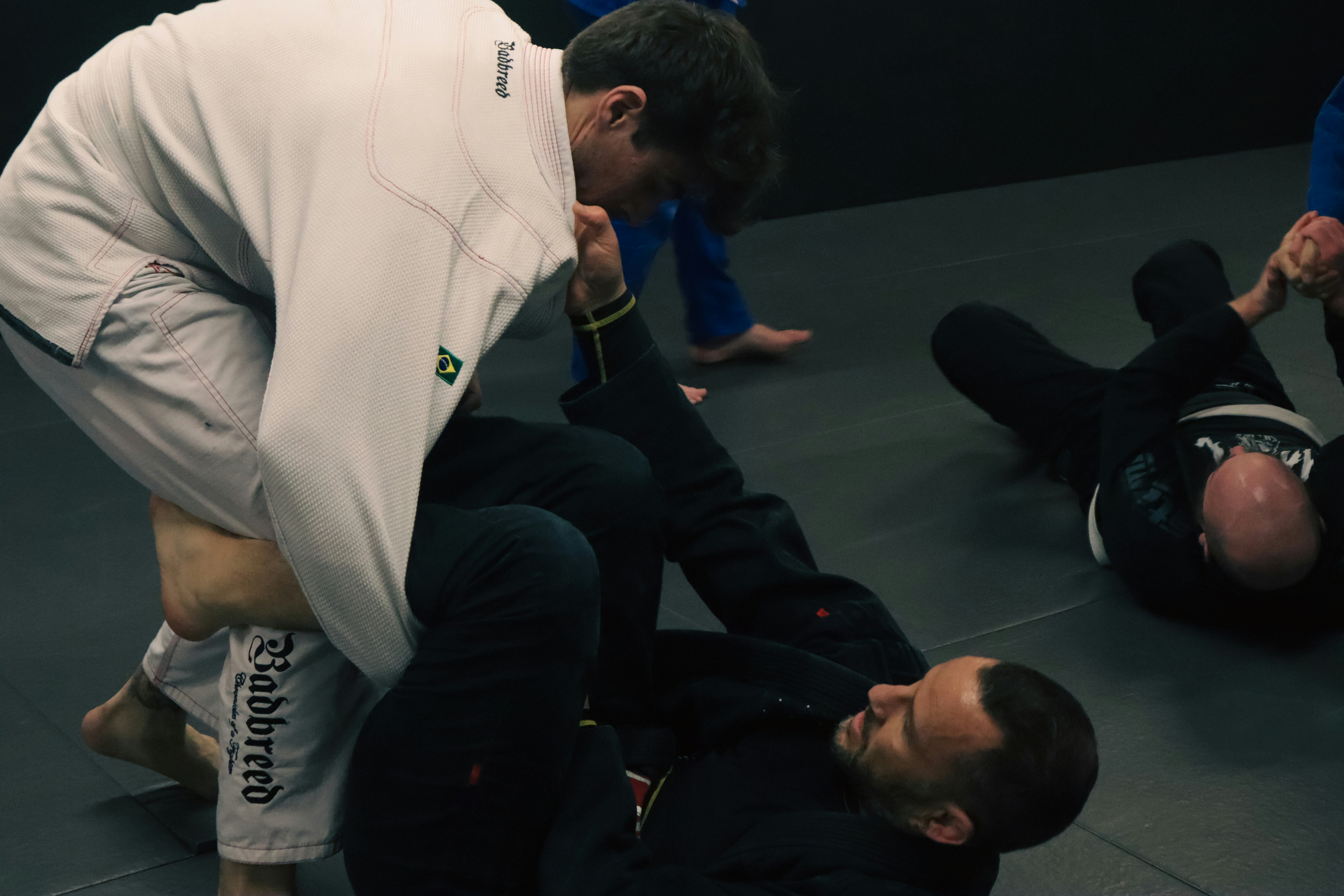 A man in white shirt and black pants standing over another man in black ...