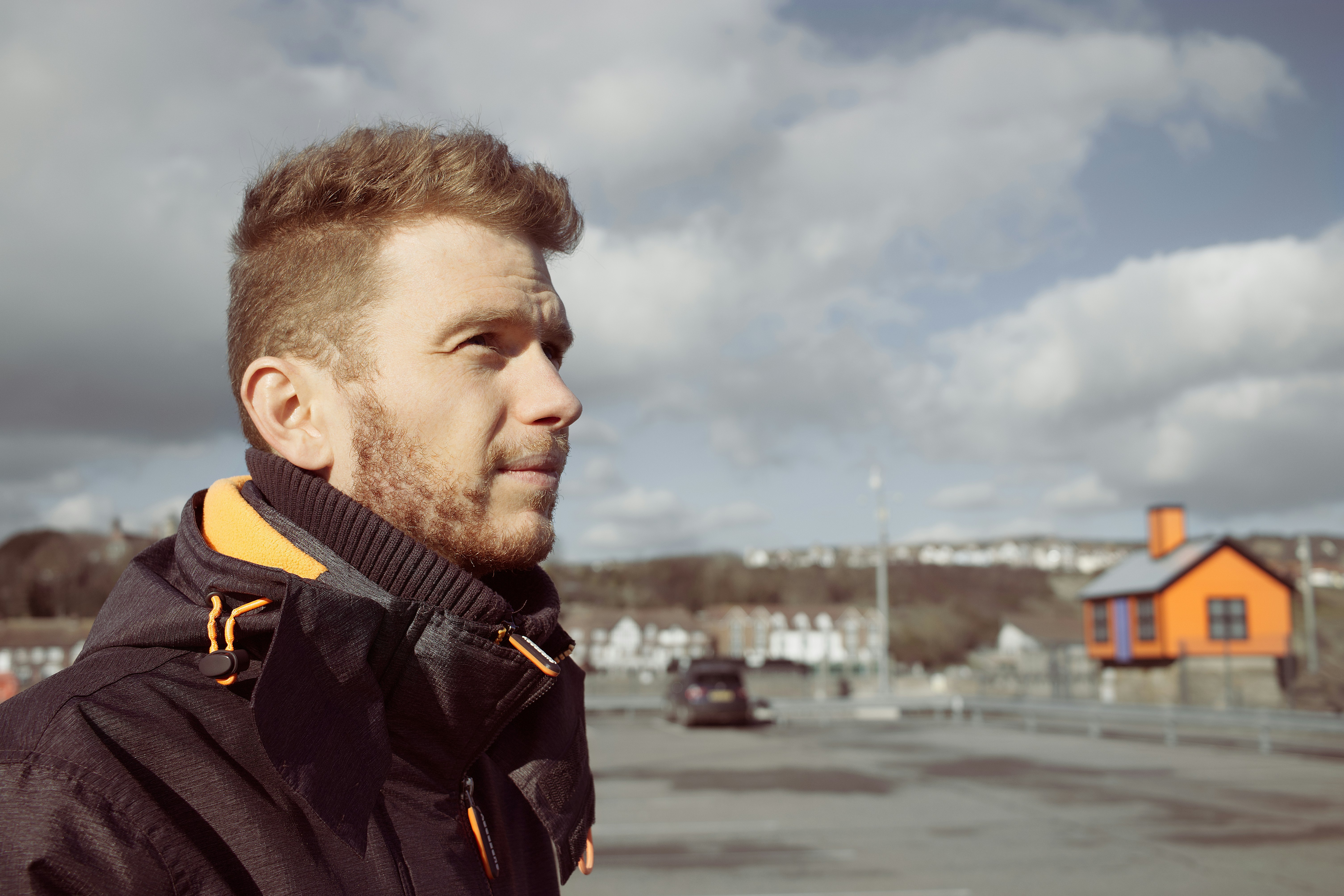 A man standing in a parking lot with a house in the background photo ...