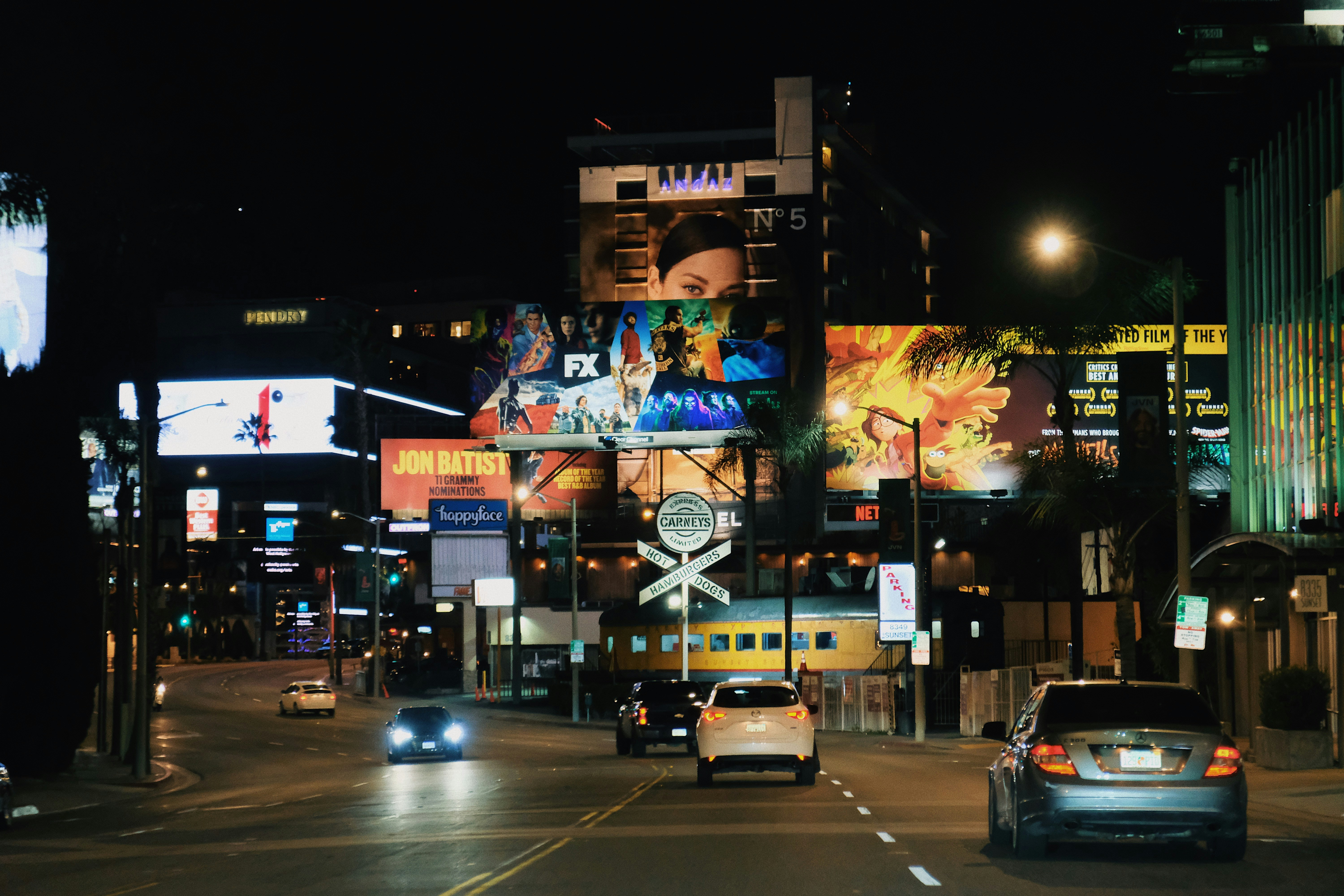 Vibrant city street illuminated by colorful billboards at night, showcasing various advertisements and a lively atmosphere.