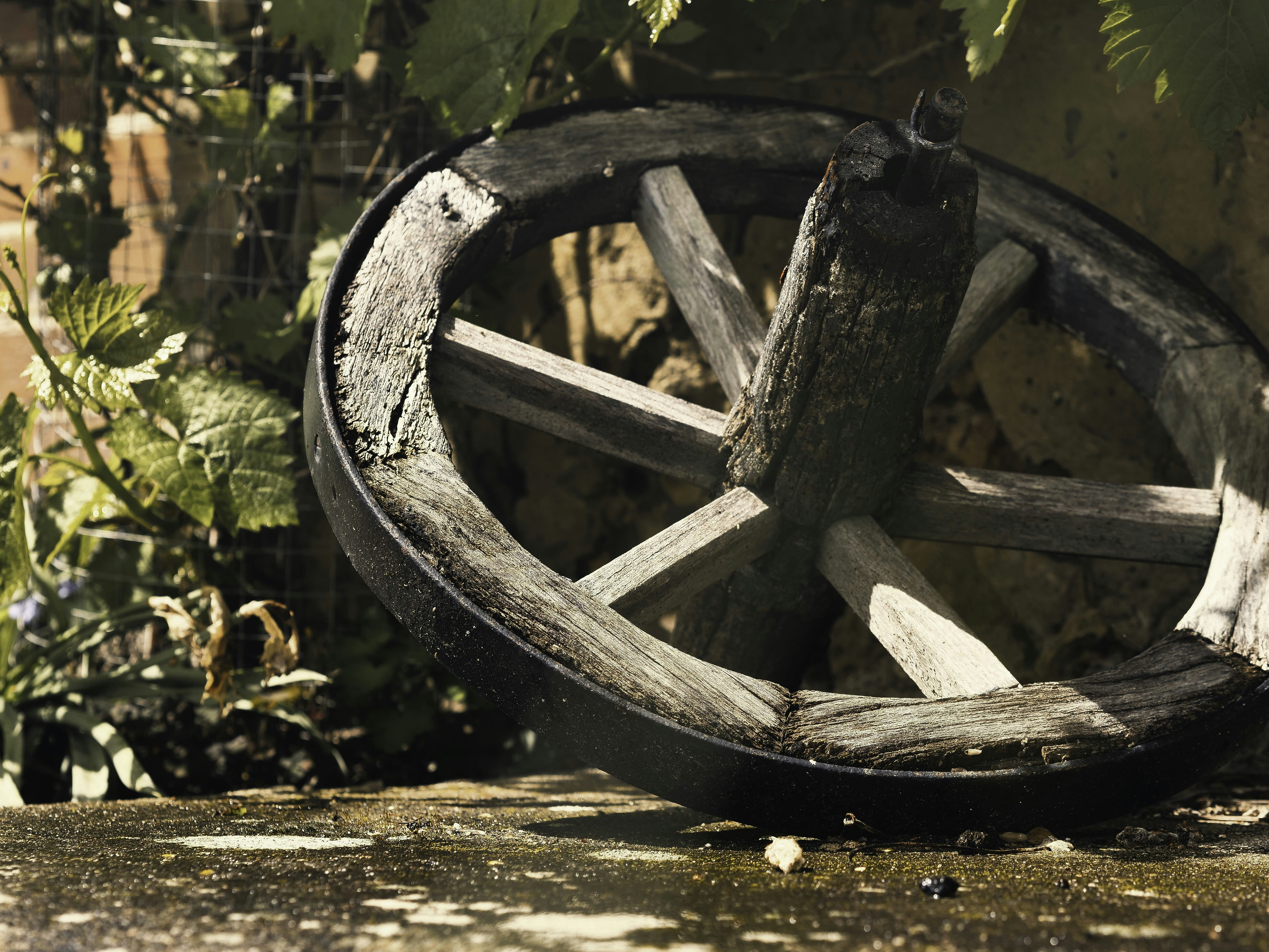 a wooden wheel sitting on top of a cement ground