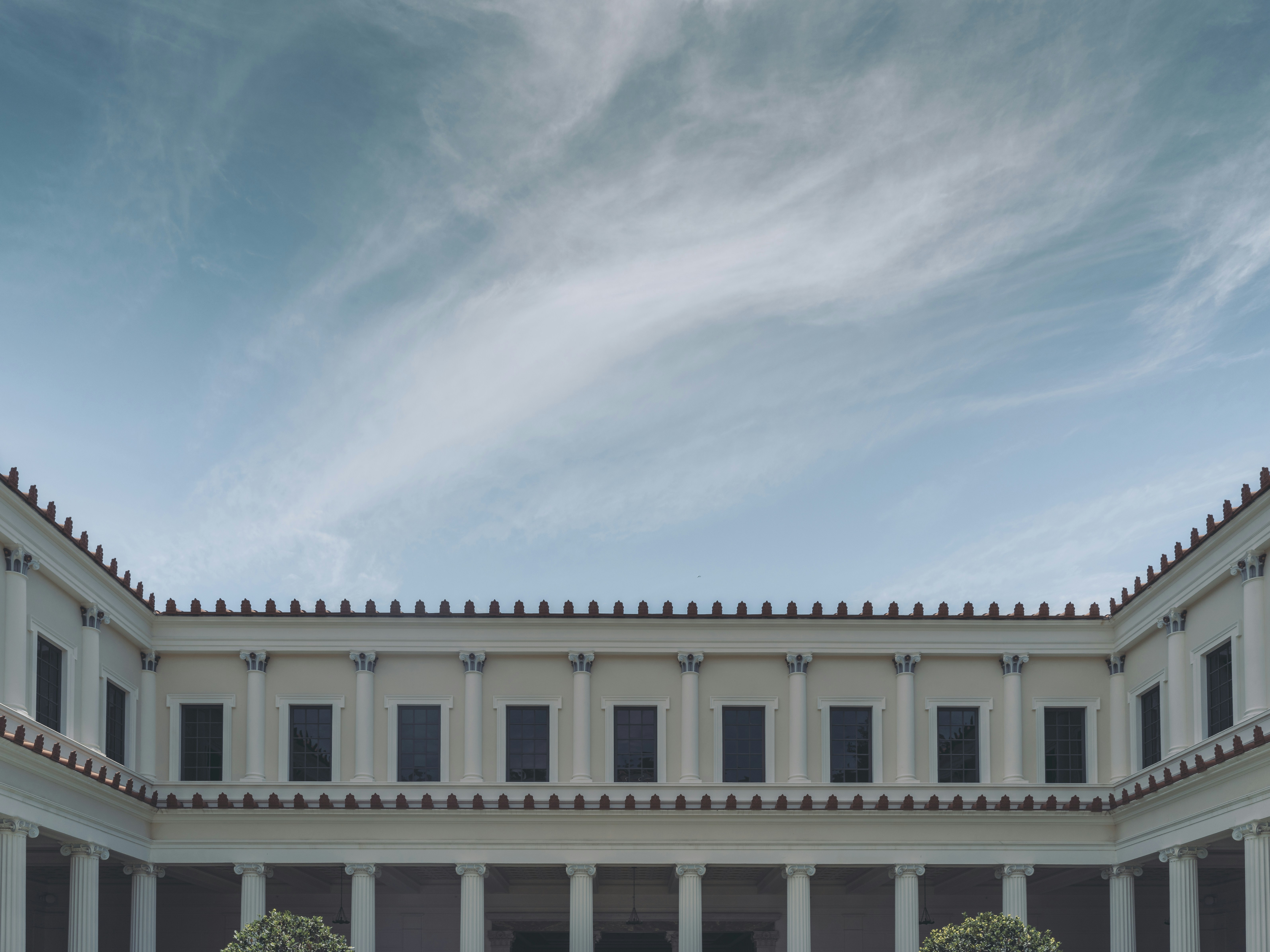 Elegant building facade with classical columns and a clear sky, emphasizing architectural symmetry and design.
