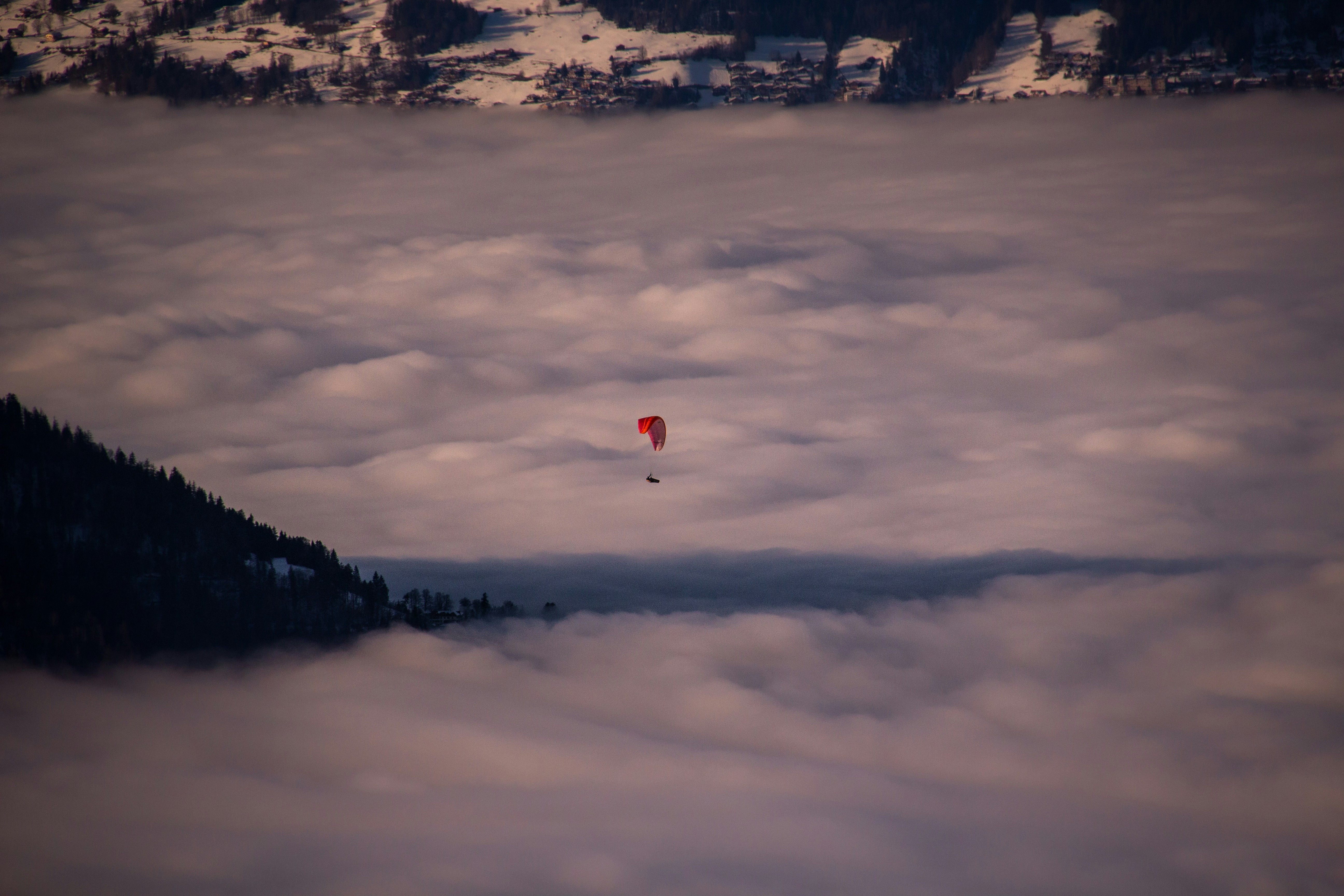Red Parachute Above a Sea of Clouds Over an Alpine Ridge