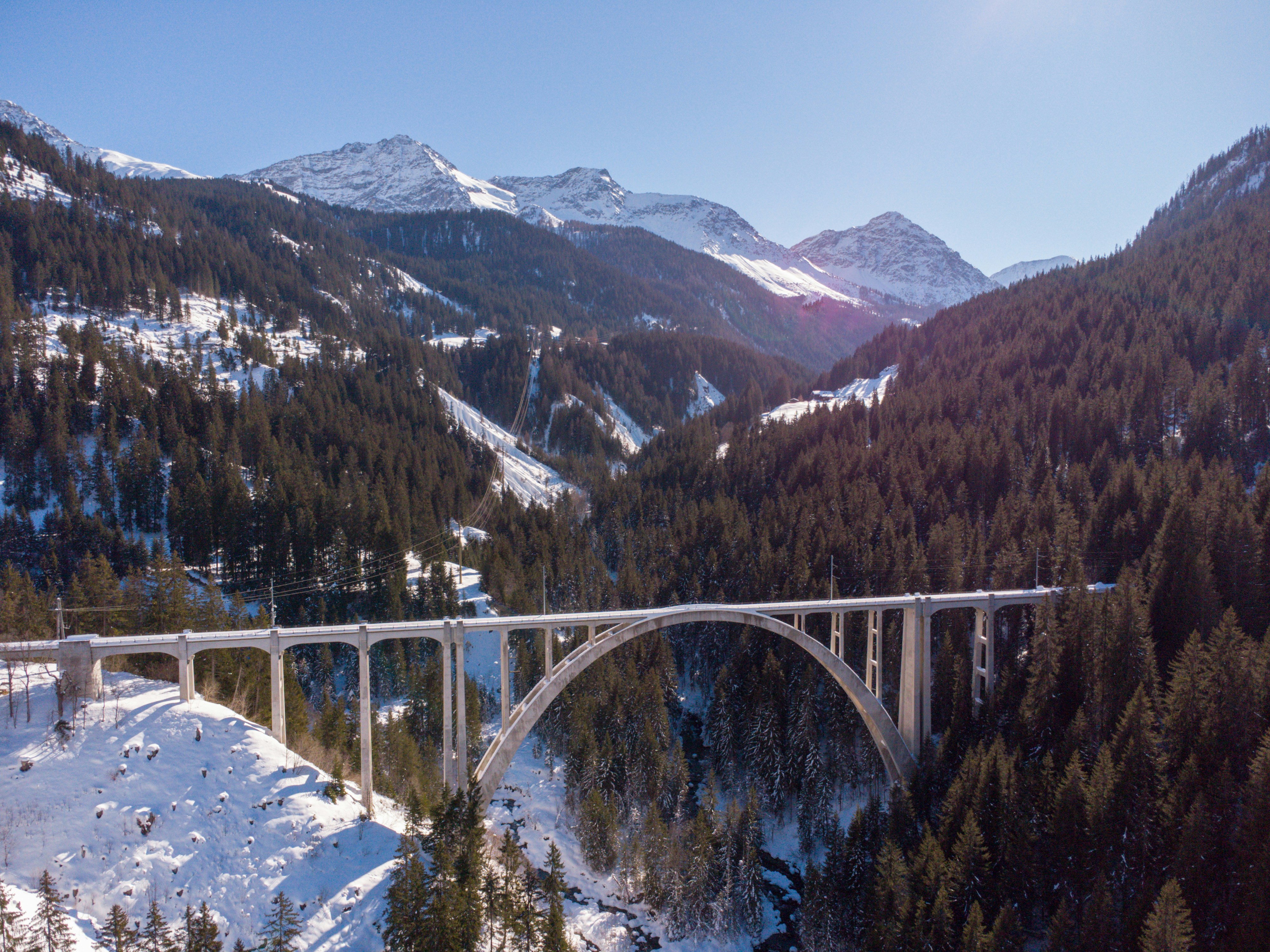A bridge in the middle of a snowy mountain range photo – Free Langwies ...