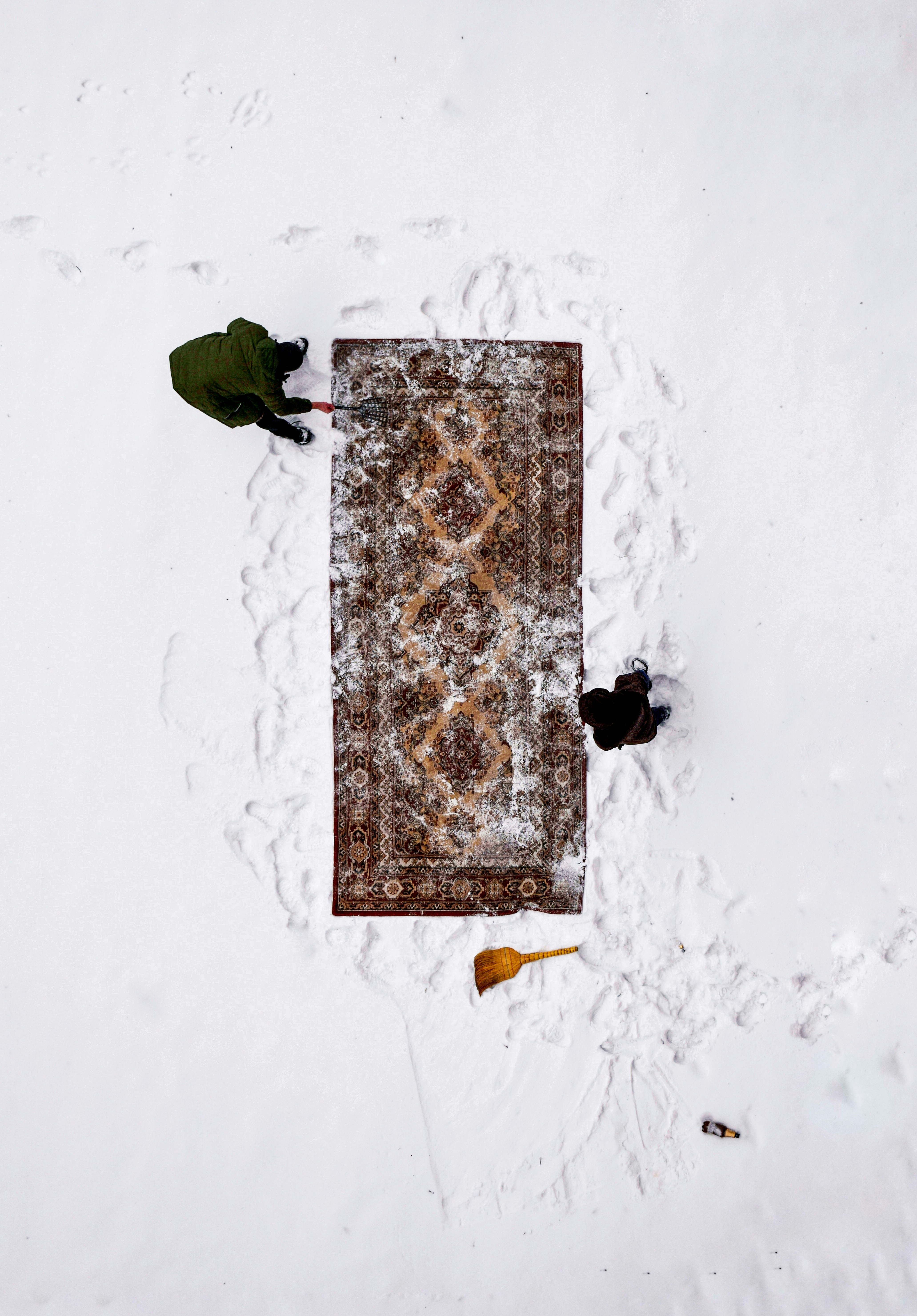 Snowy Carpet: Two Figures on a Rug Mid-Stride Across a Blank White Field