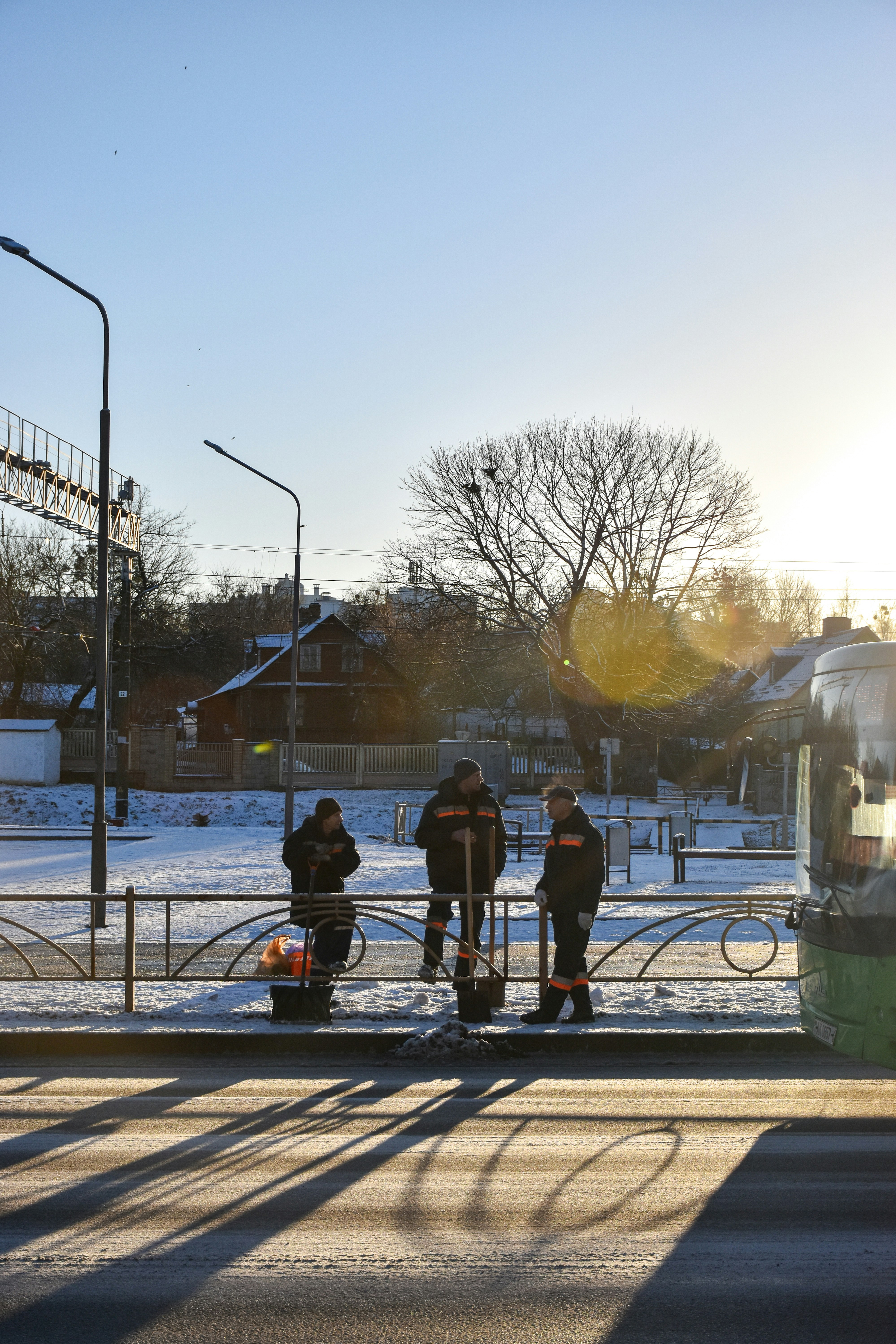 Dusk on Snow: Trio by the Rail With a Green Bus