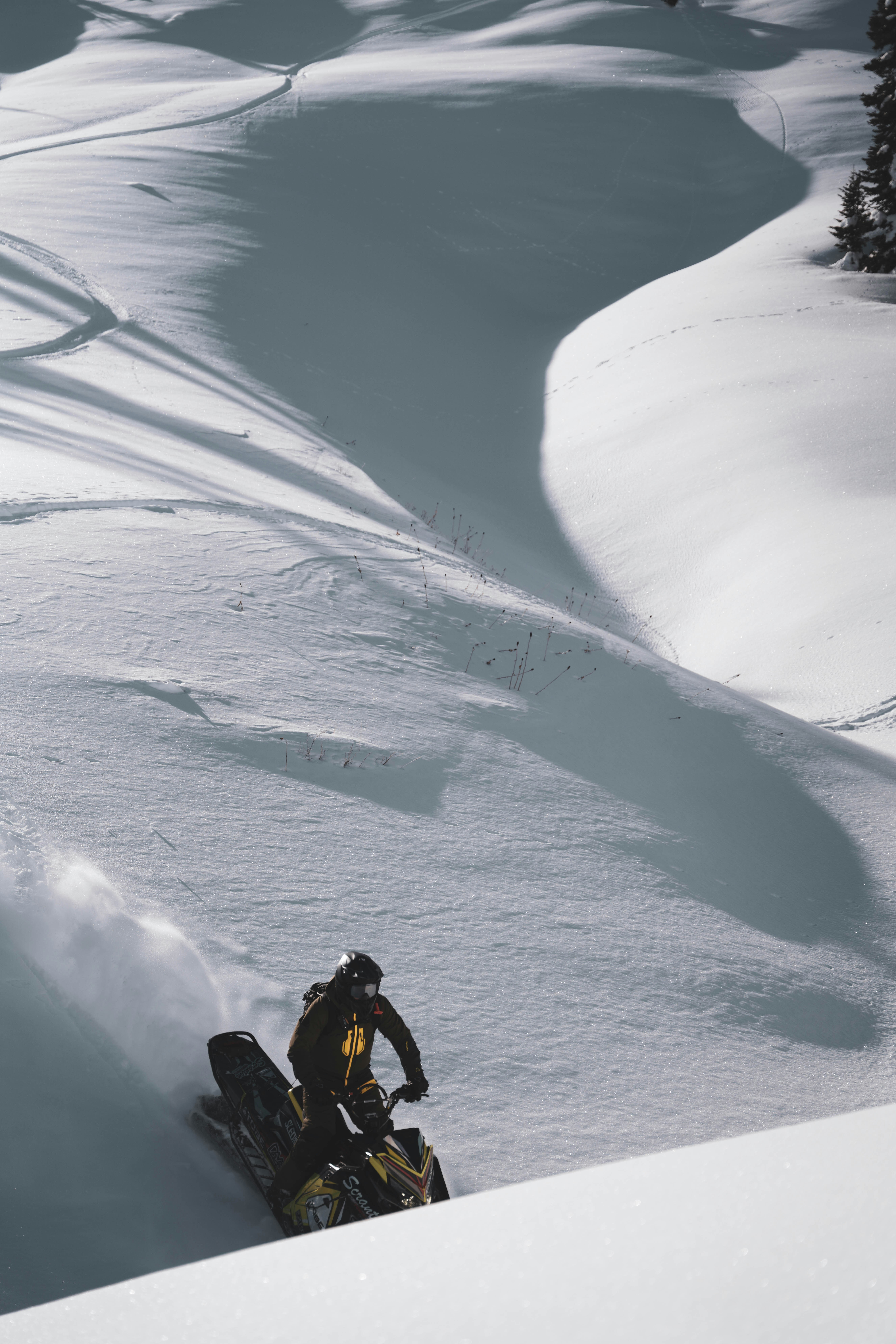 A man riding a snowmobile down a snow covered slope photo – Free Grey ...