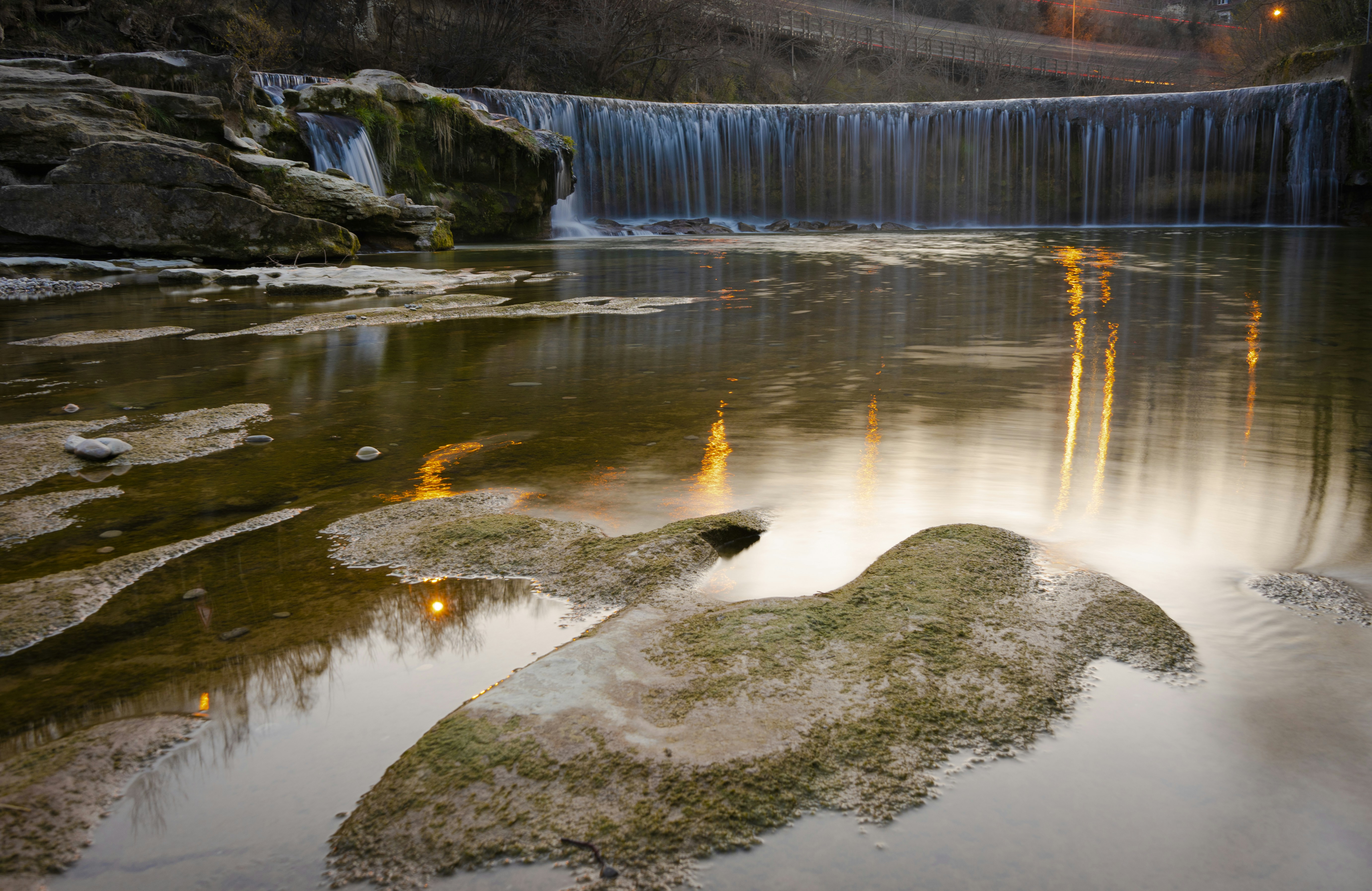 A small waterfall with lights reflecting in the water photo – Free ...