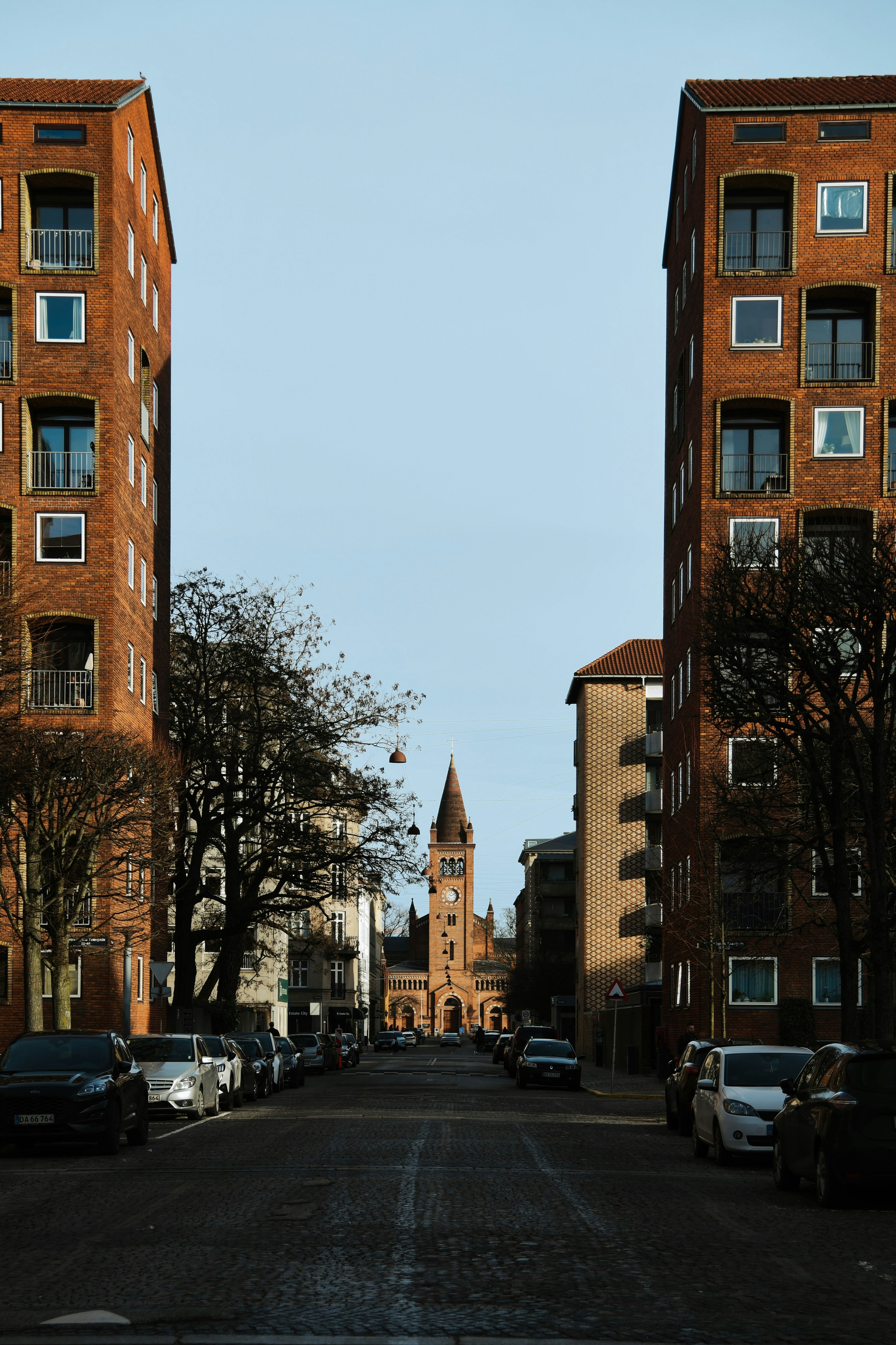 Brick buildings frame a picturesque street leading to a historic clock tower in the distance.
