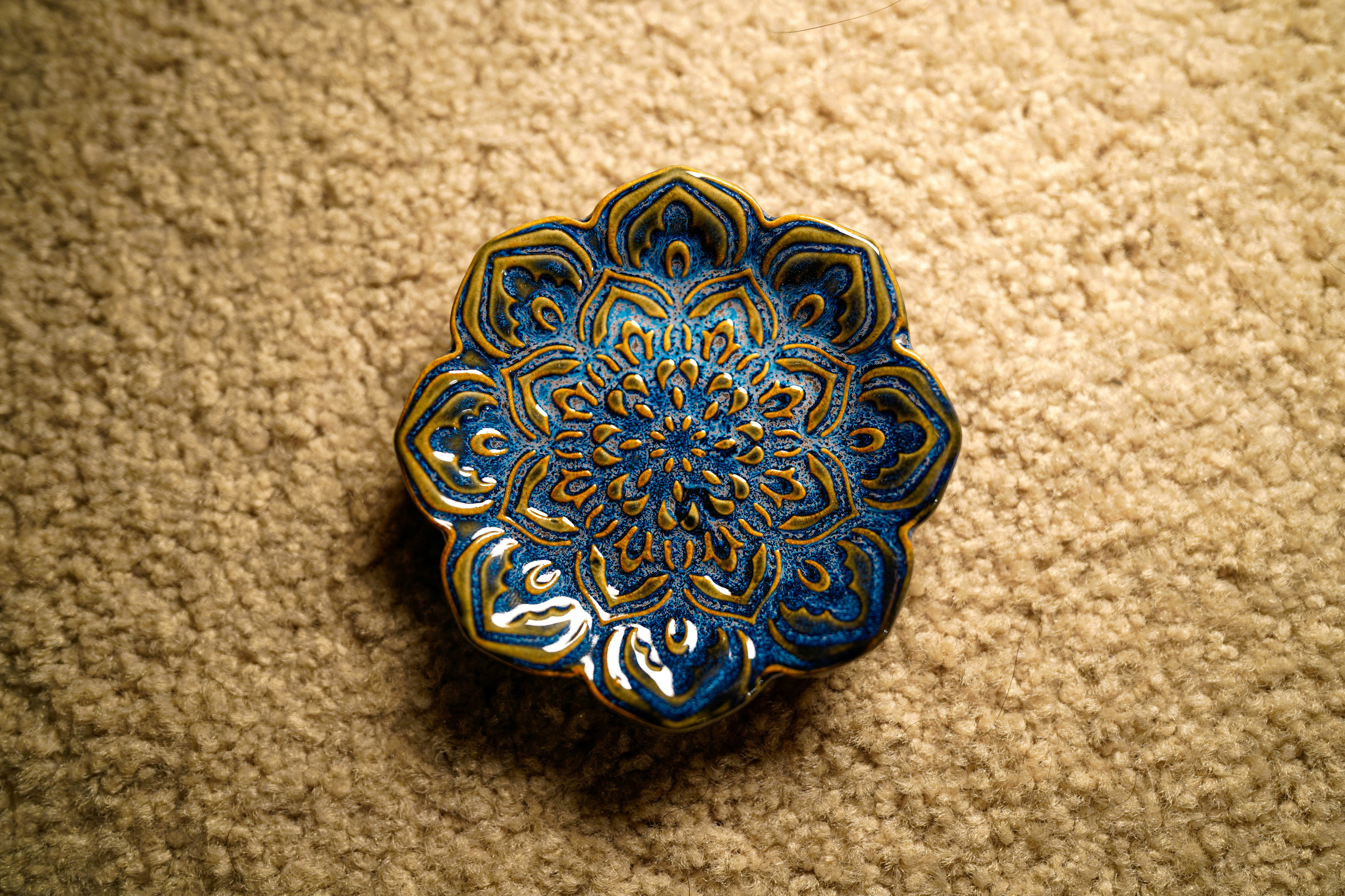 a blue flower brooch sitting on top of a carpet